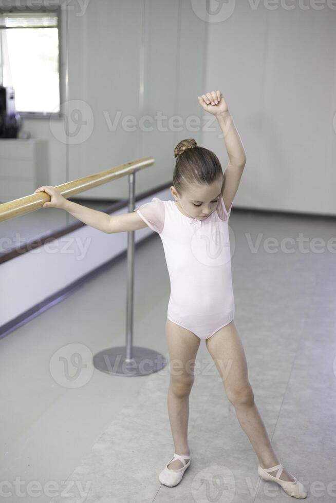 Cute little girl toddler ballerina in pale pink tutu and ballet shoes practicing dance moves ...
