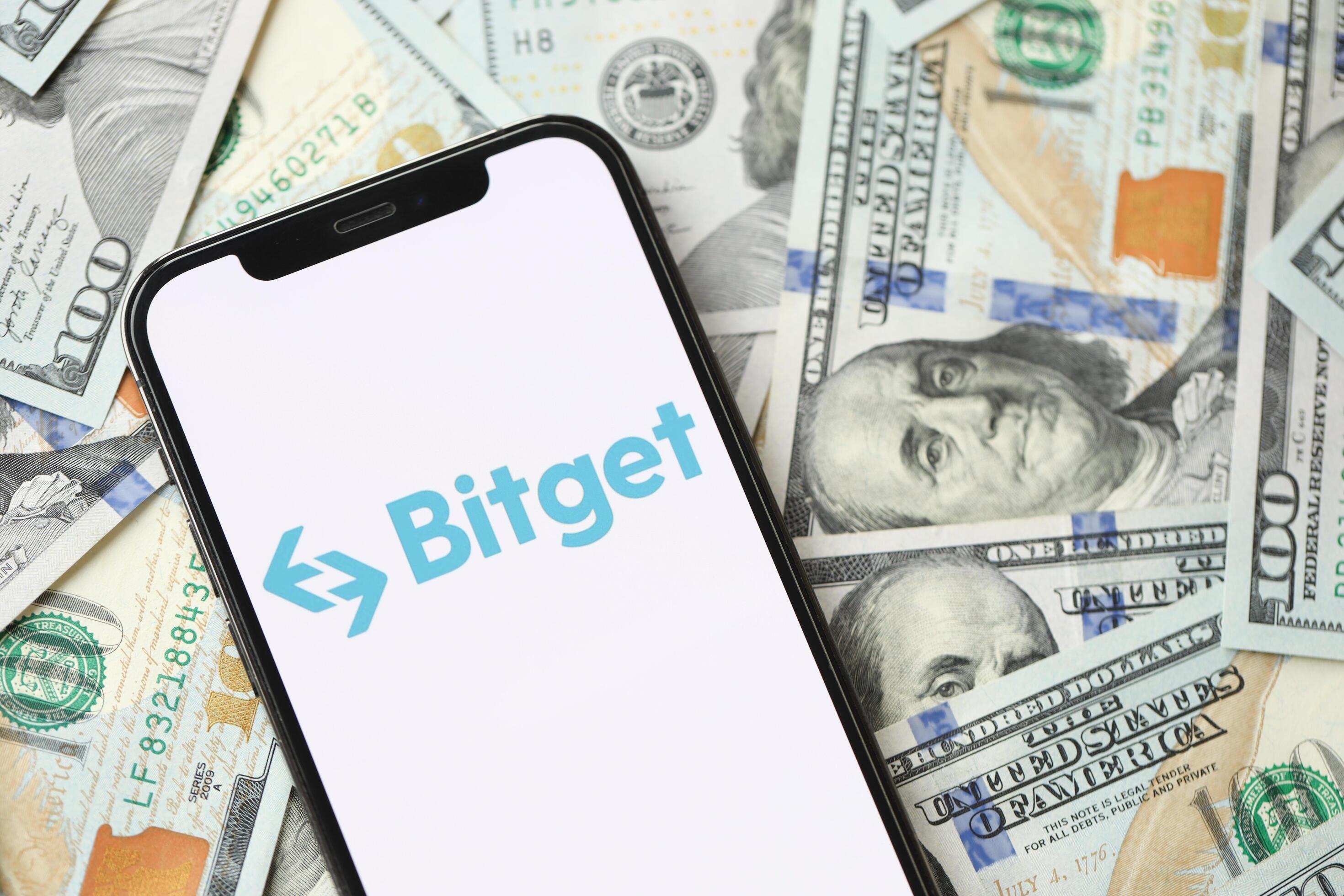 KYIV, UKRAINE - MARCH 15, 2024 Bitget logo on iPhone display screen with many hundred dollar ...