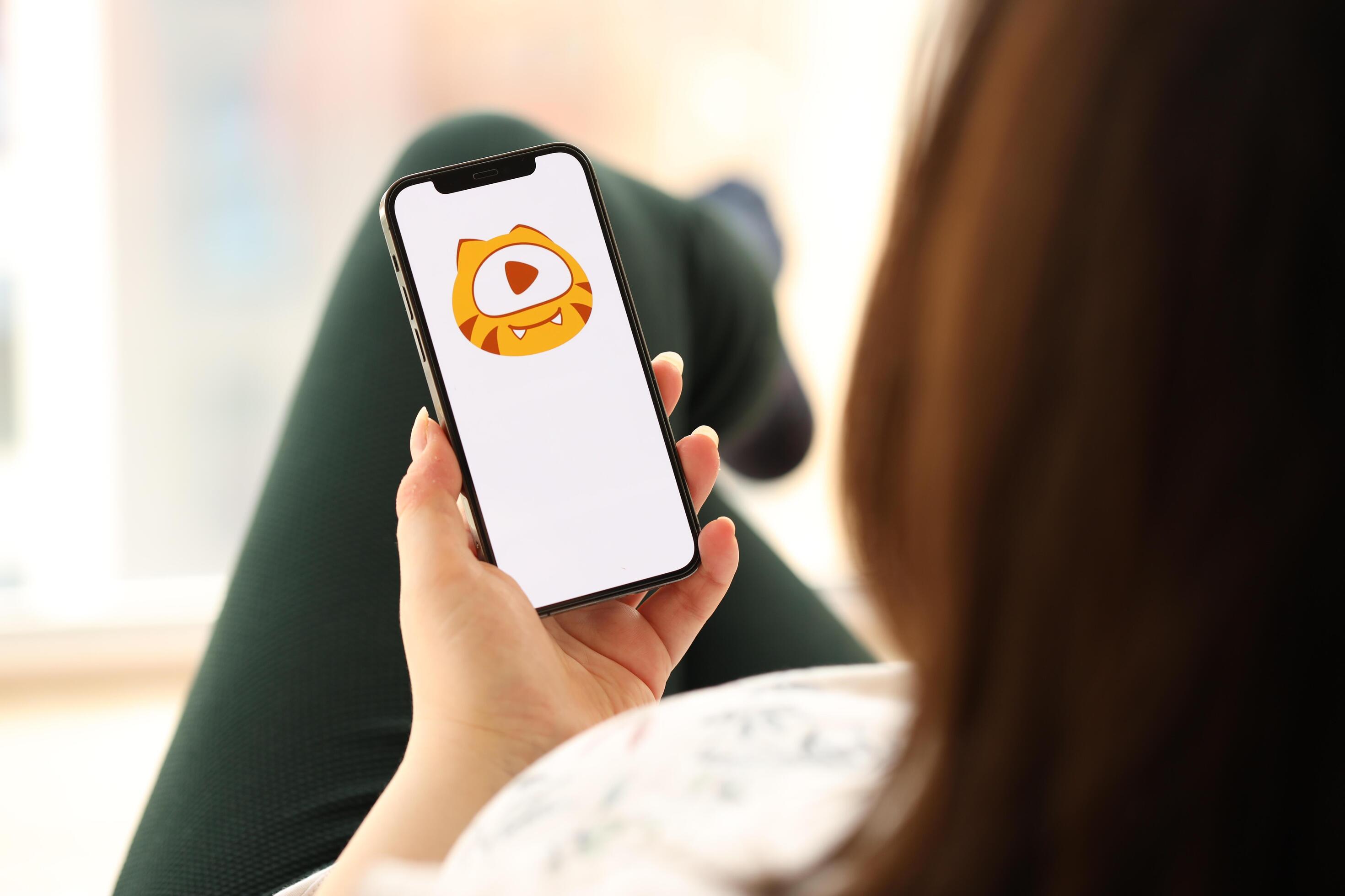 KYIV, UKRAINE - APRIL 1, 2024 Huya icon on smartphone screen in young female hands 47641830 ...