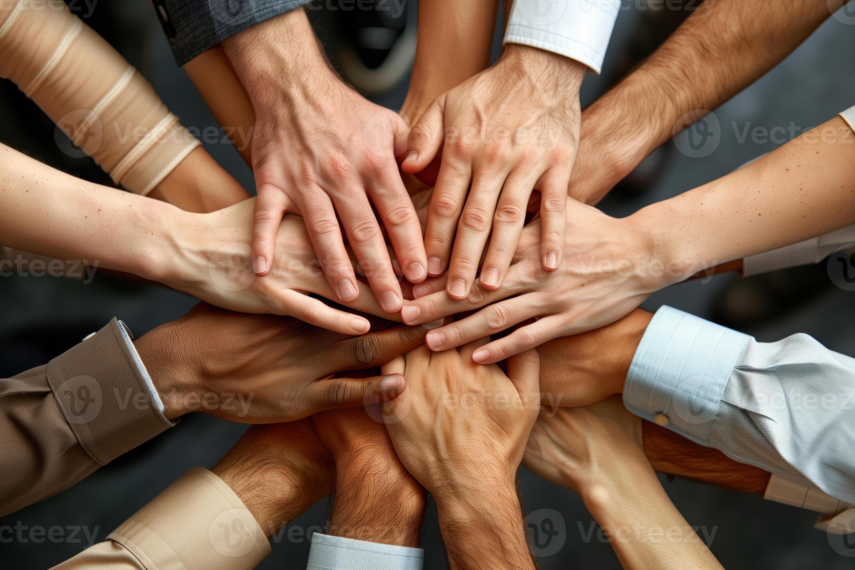 A close-up image of multiple hands, each with different skin tones, reaching together in a ...