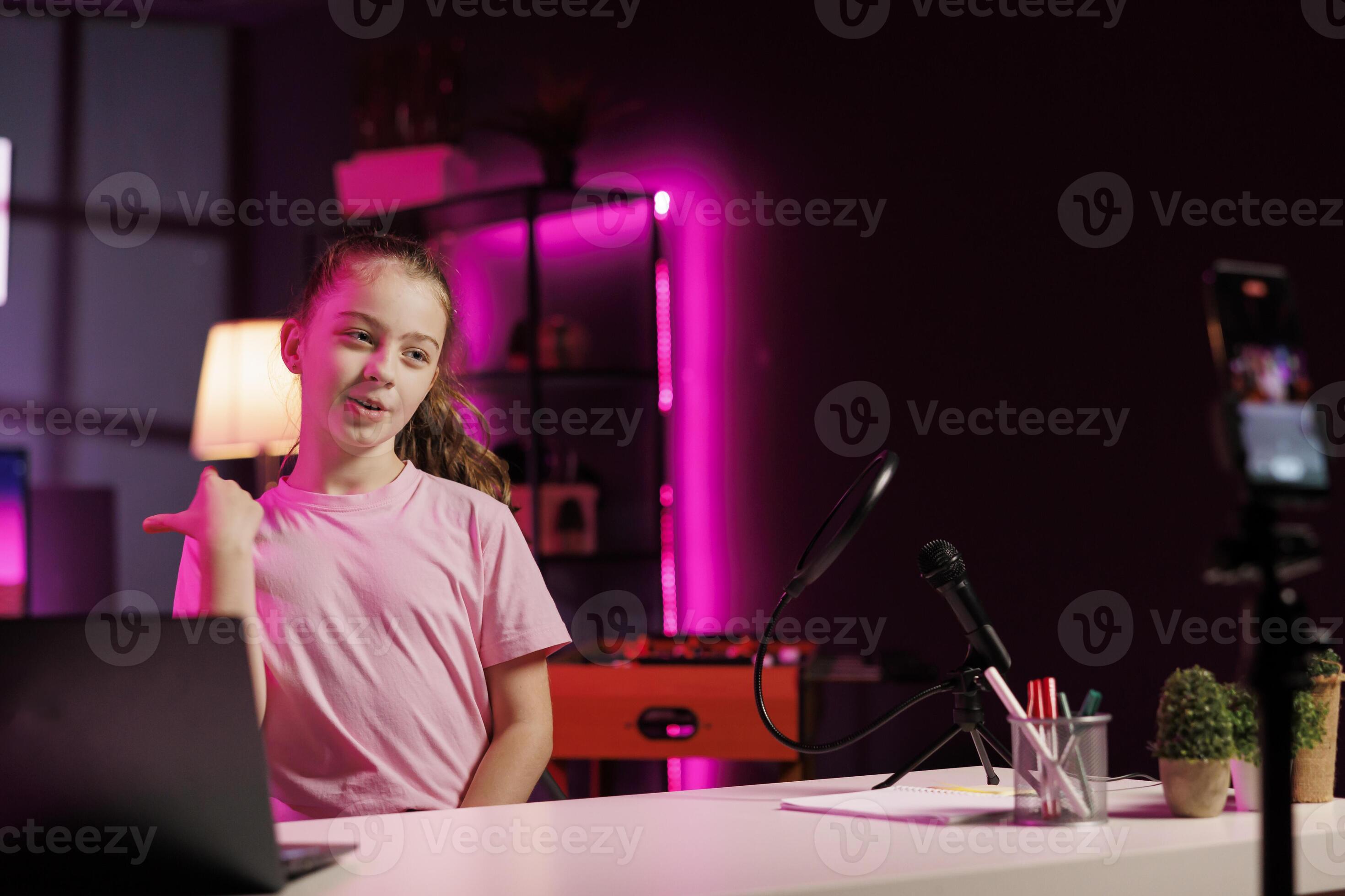 Cute girl doing content creation, using cellphone on tripod stabilizer to film vlog channel ...