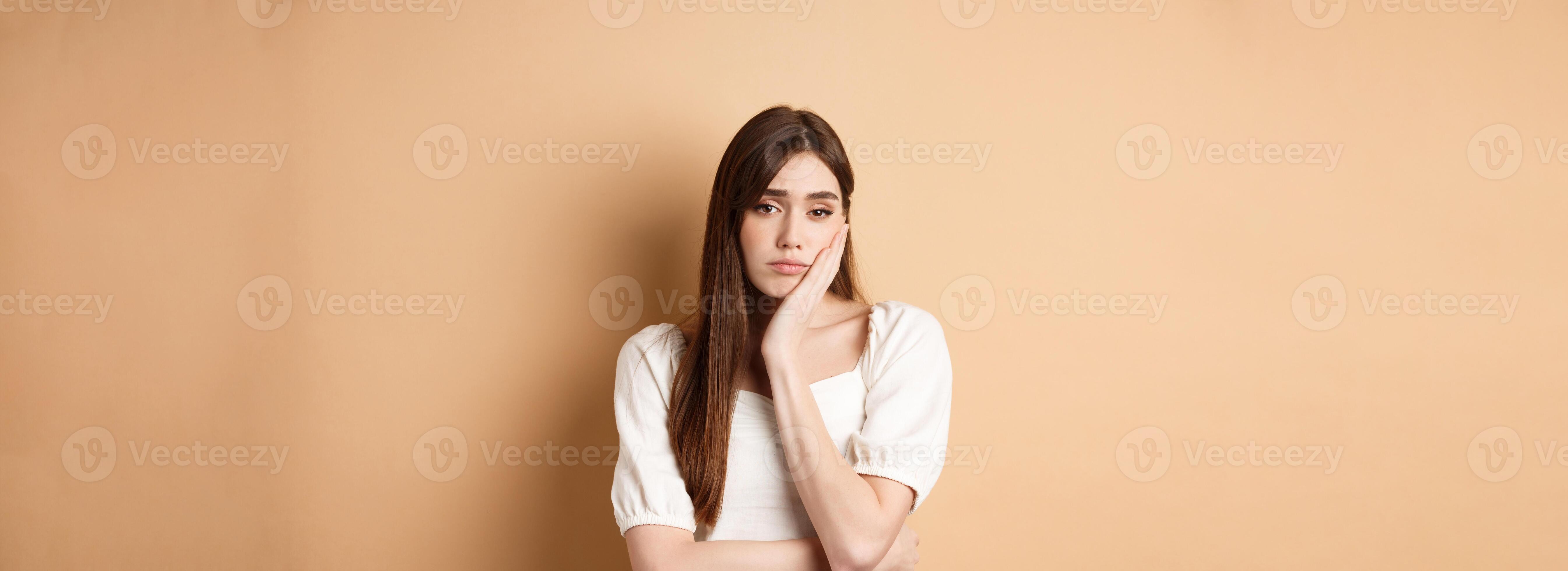 Bored and tired young woman looking indifferent at camera, lean face on ...