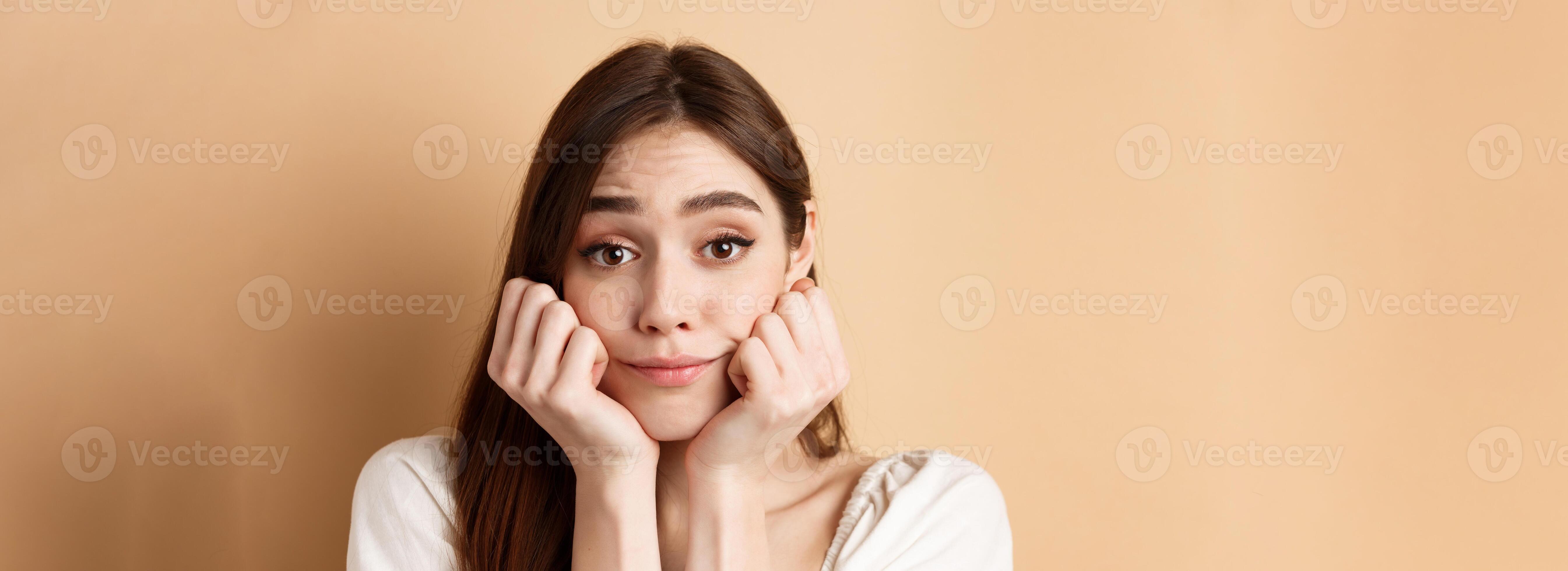 Close-up of cute and pretty girl lean face on hands, looking at camera ...