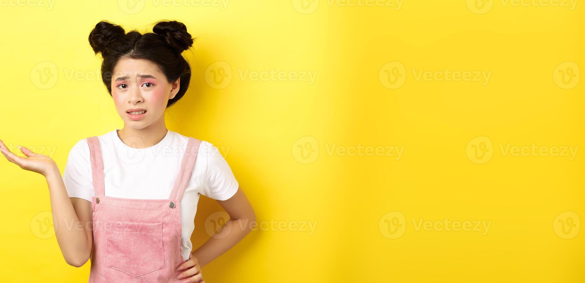 Confused teen asian girl with bright makeup and summer clothes, raising ...