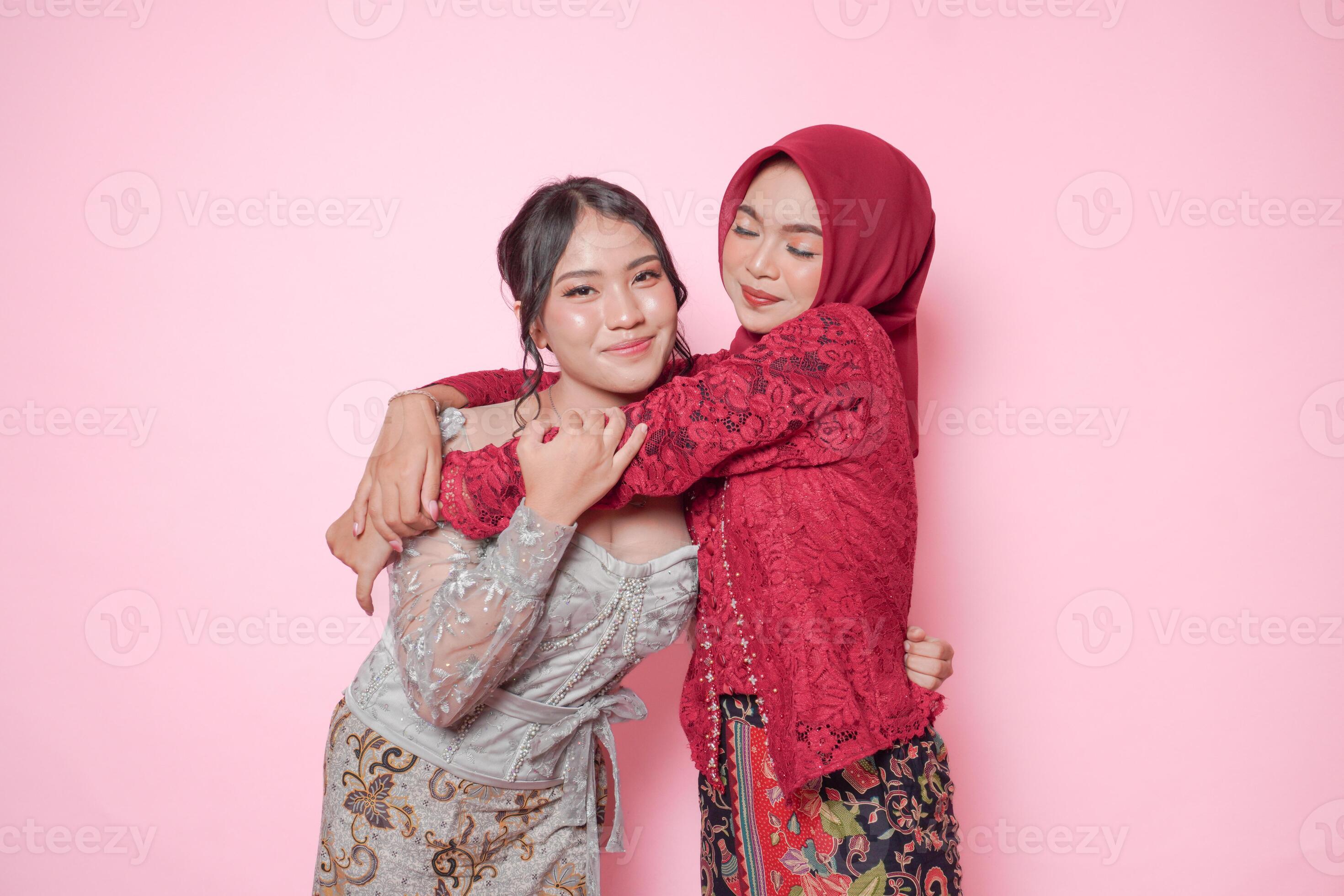 Happy two Asian young woman as close friends wearing modern kebaya and hugging each other ...