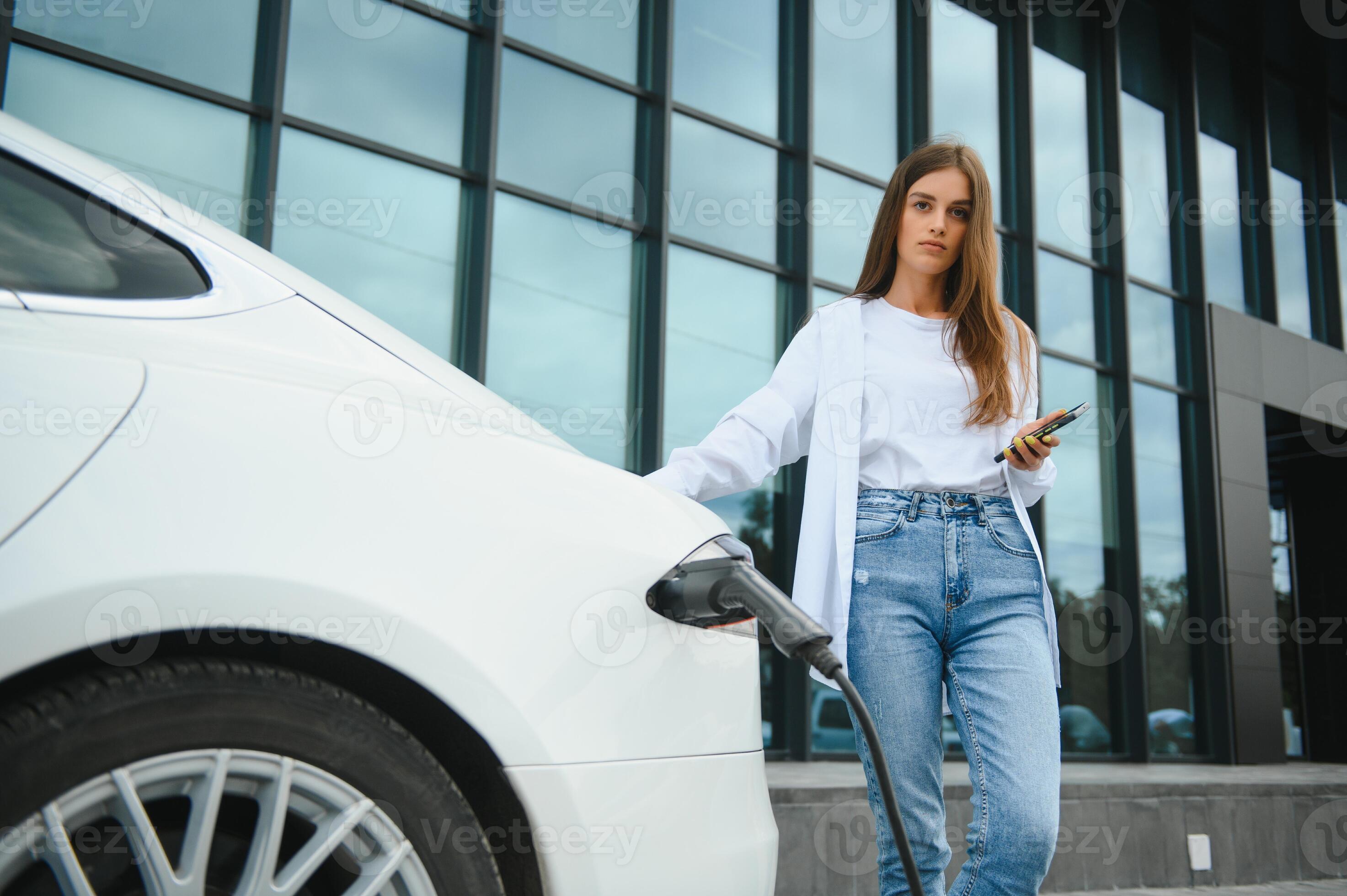 Electric car charging in street. Ecological Car Connected and Charging Batteries. Girl Waiting ...