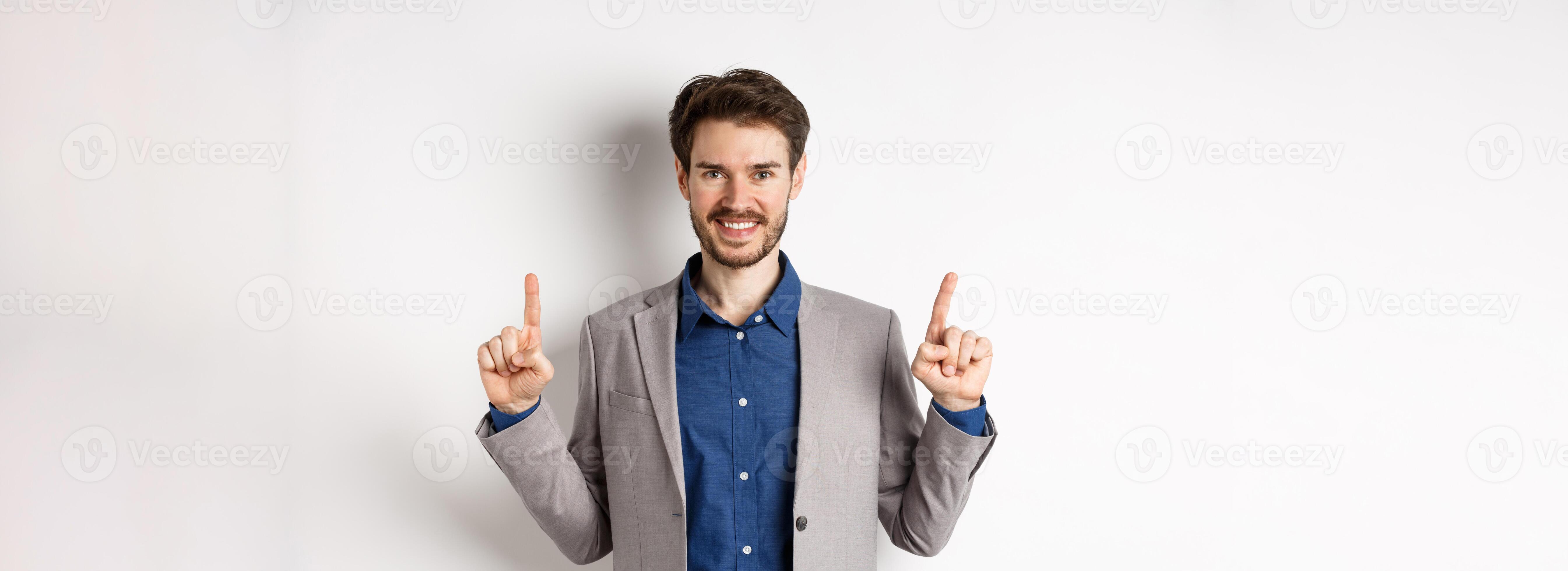 Confident successful businessman pointing fingers up, smiling and ...
