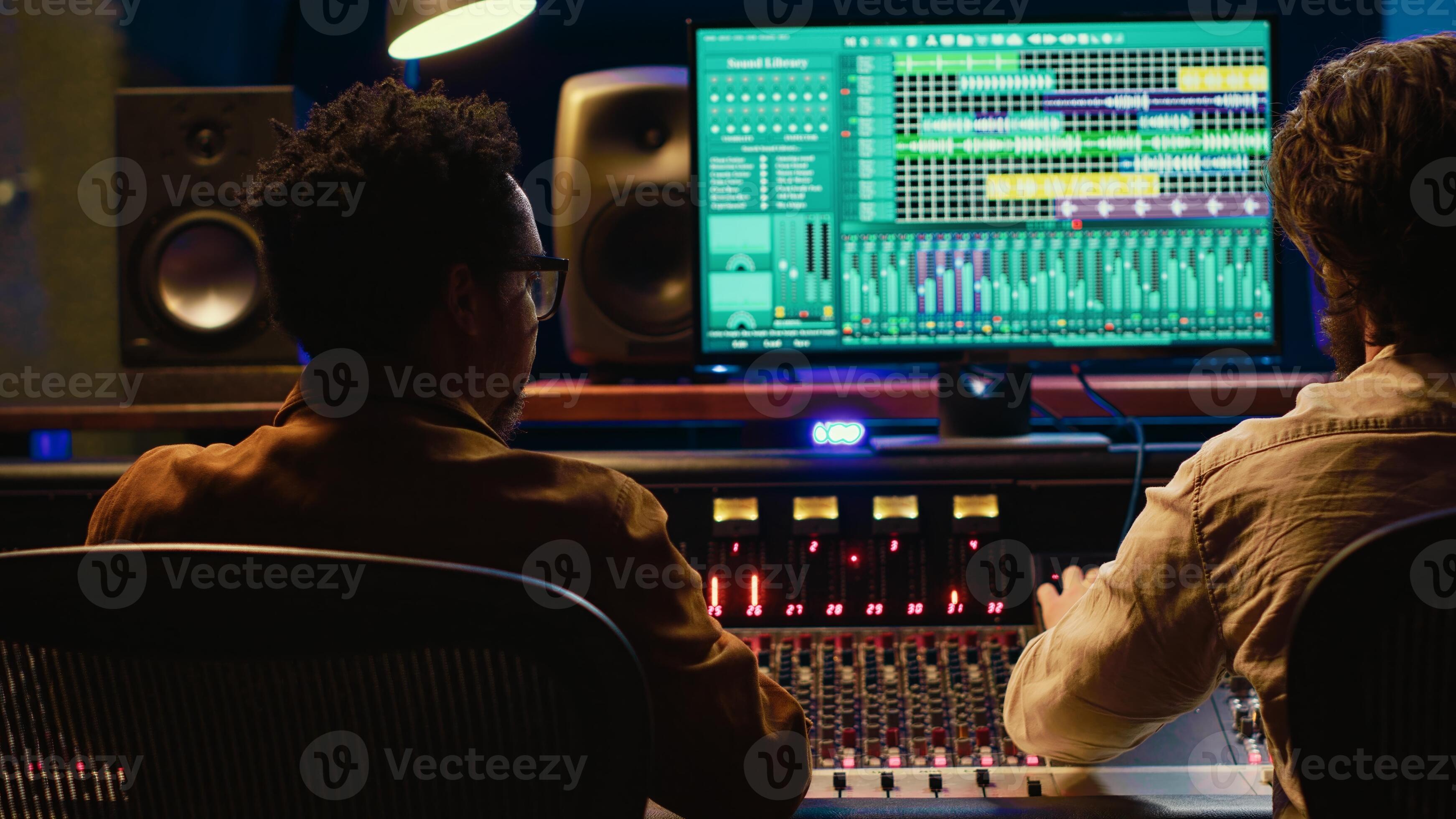 Diverse team collaborating on creating a new hit song in control room ...