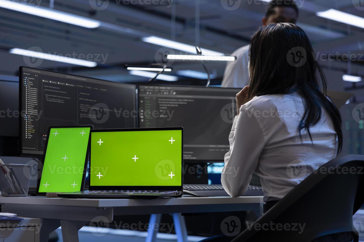 Technician in data center using isolated screen tablet and laptop to check for server issues ...