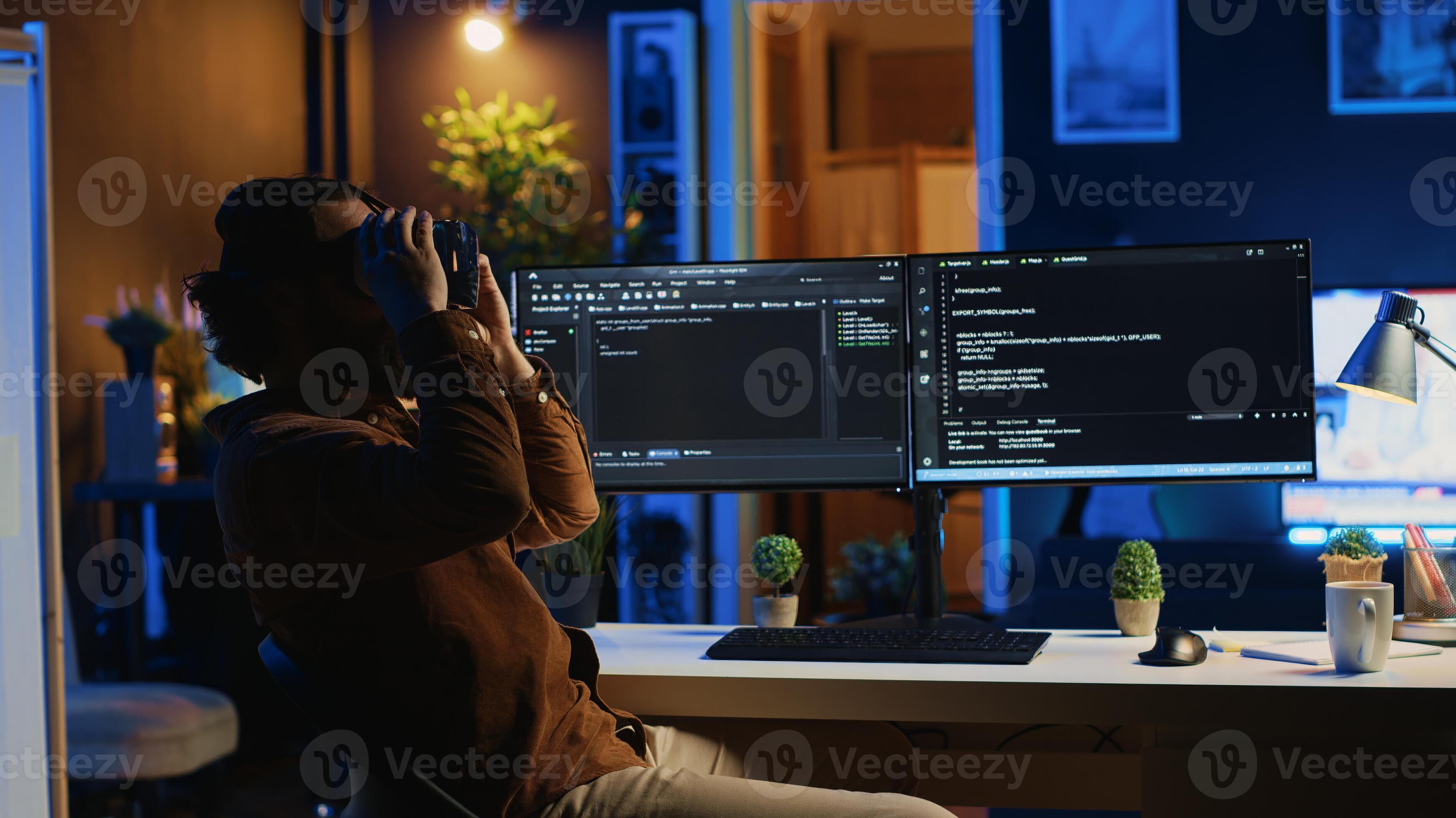 Teleworking programmer using futuristic VR glasses in home office to do javascript programming ...