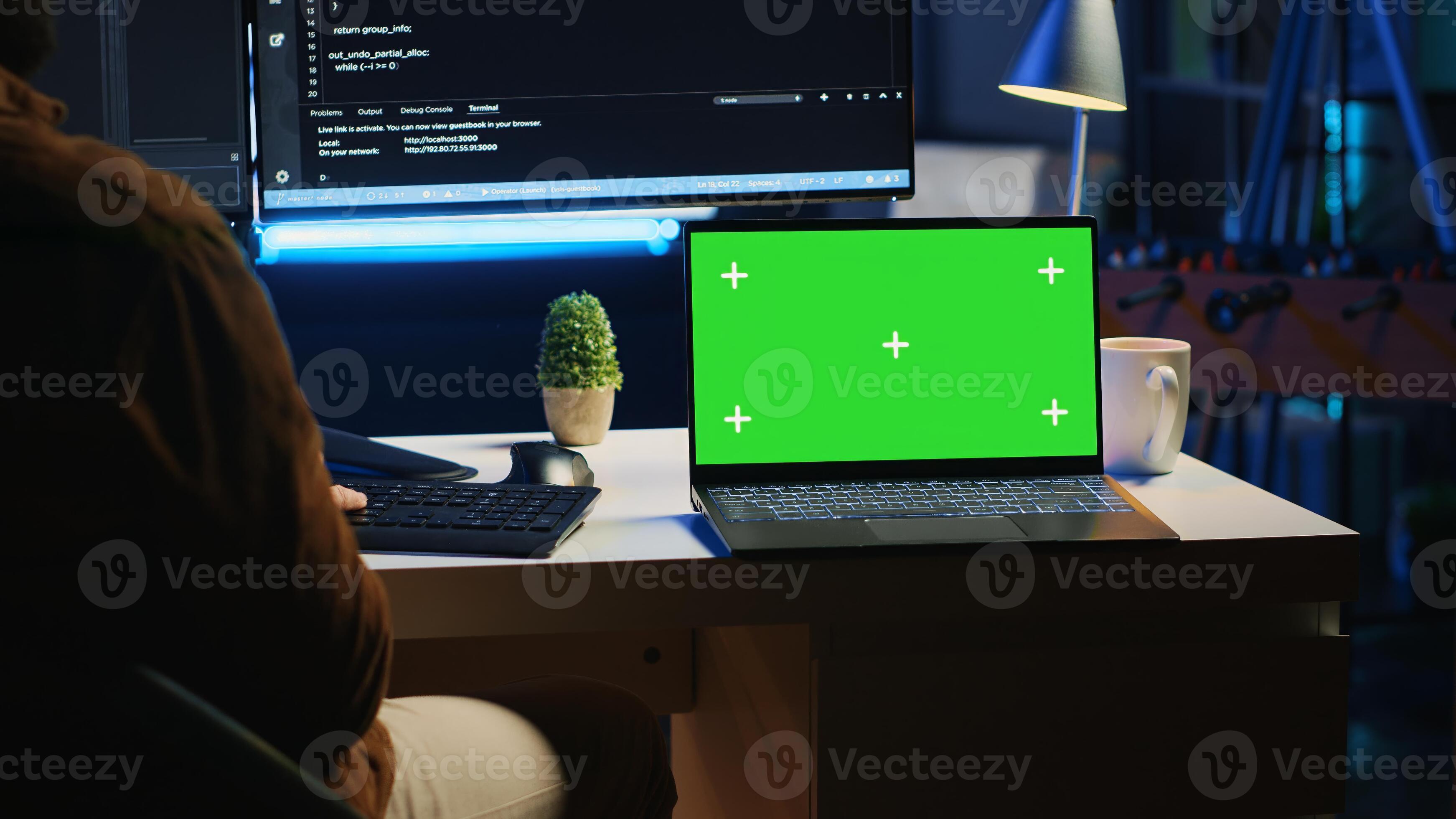 Green screen laptop next to freelancing man doing IT support job from ...