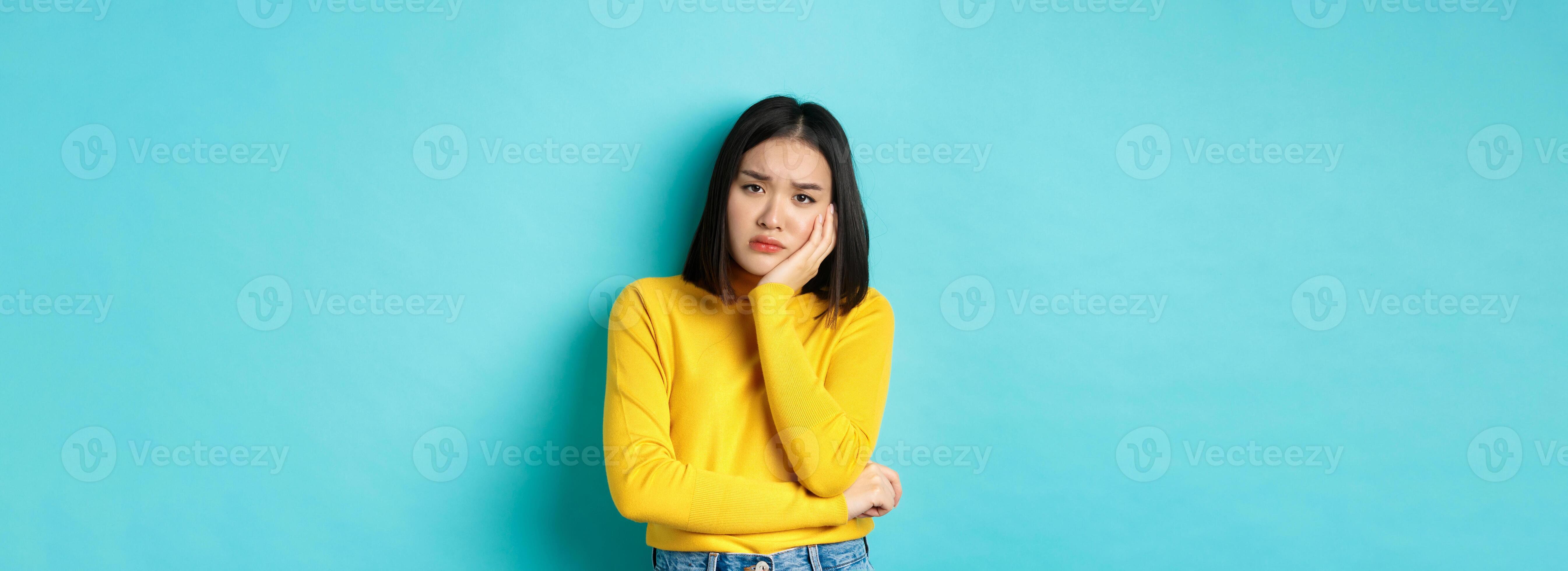 Sad and bored asian girl looking reluctant and unamused at camera ...