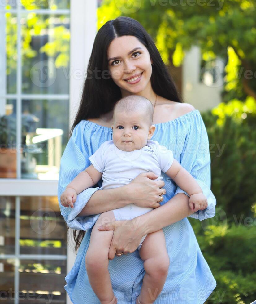 Young beautiful mother hugging her little baby son outdoors. Mom and baby boy having fun ...
