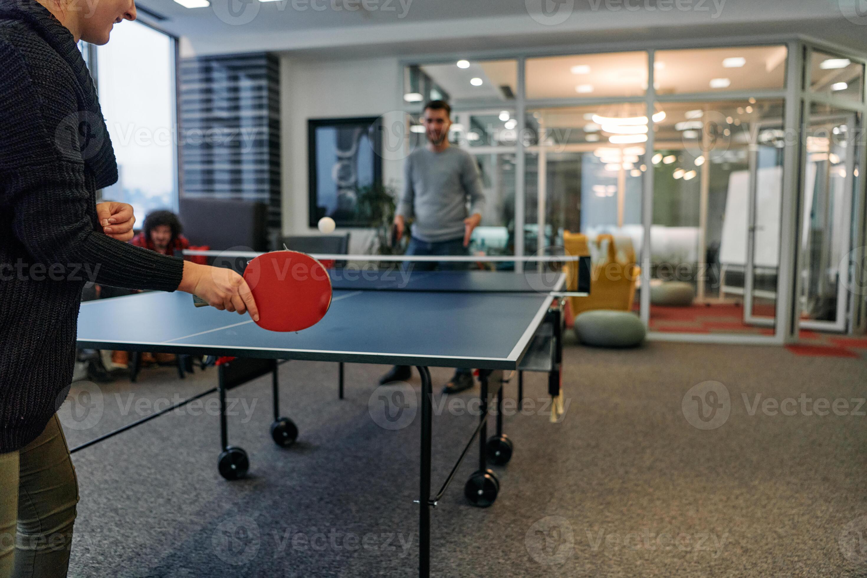 Business colleagues take a break from work to enjoy a game of table tennis fostering teamwork and camaraderie in the workplace 48760904 Stock Photo at Vecteezy