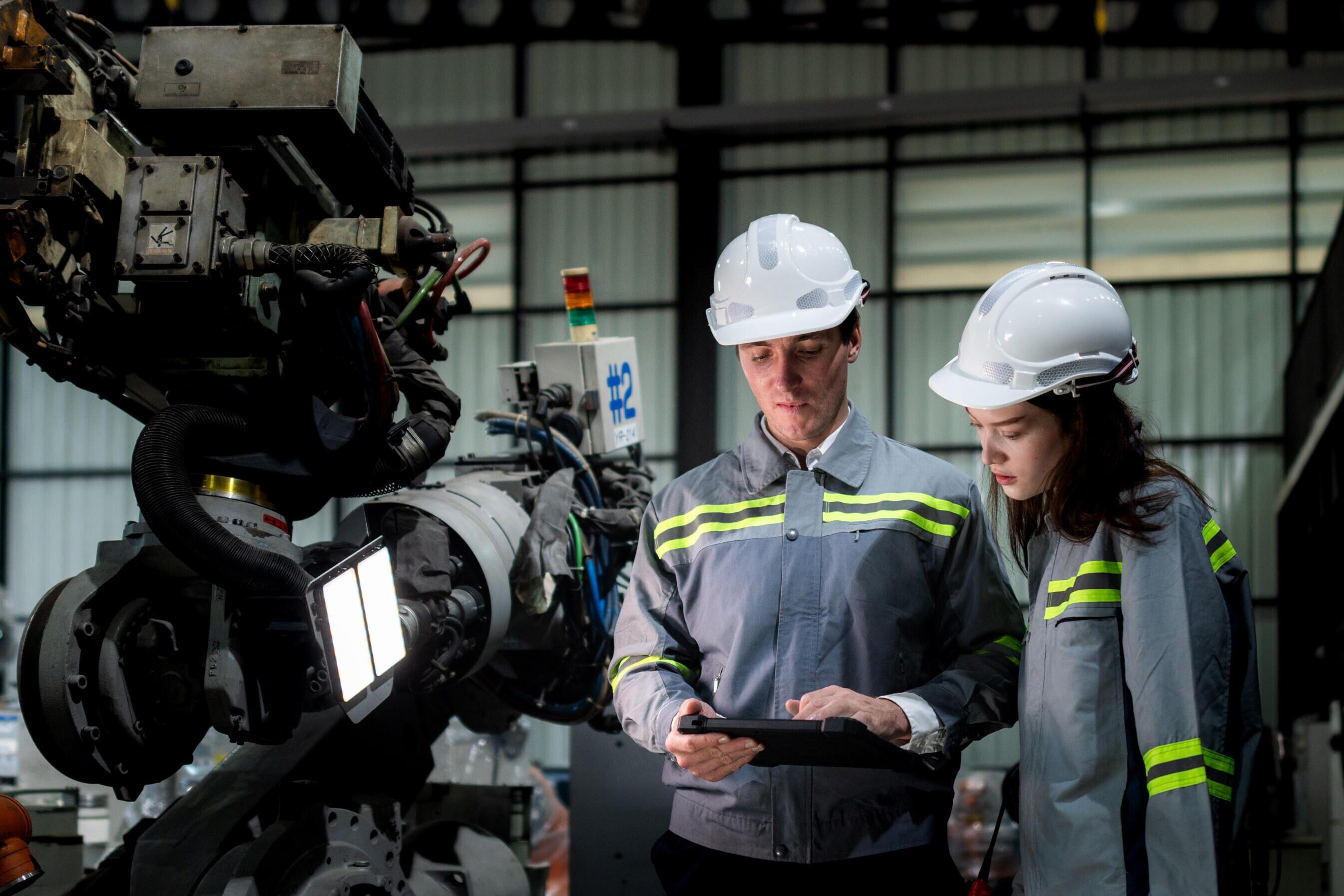 team engineers inspecting on machine with smart tablet. Worker works at ...