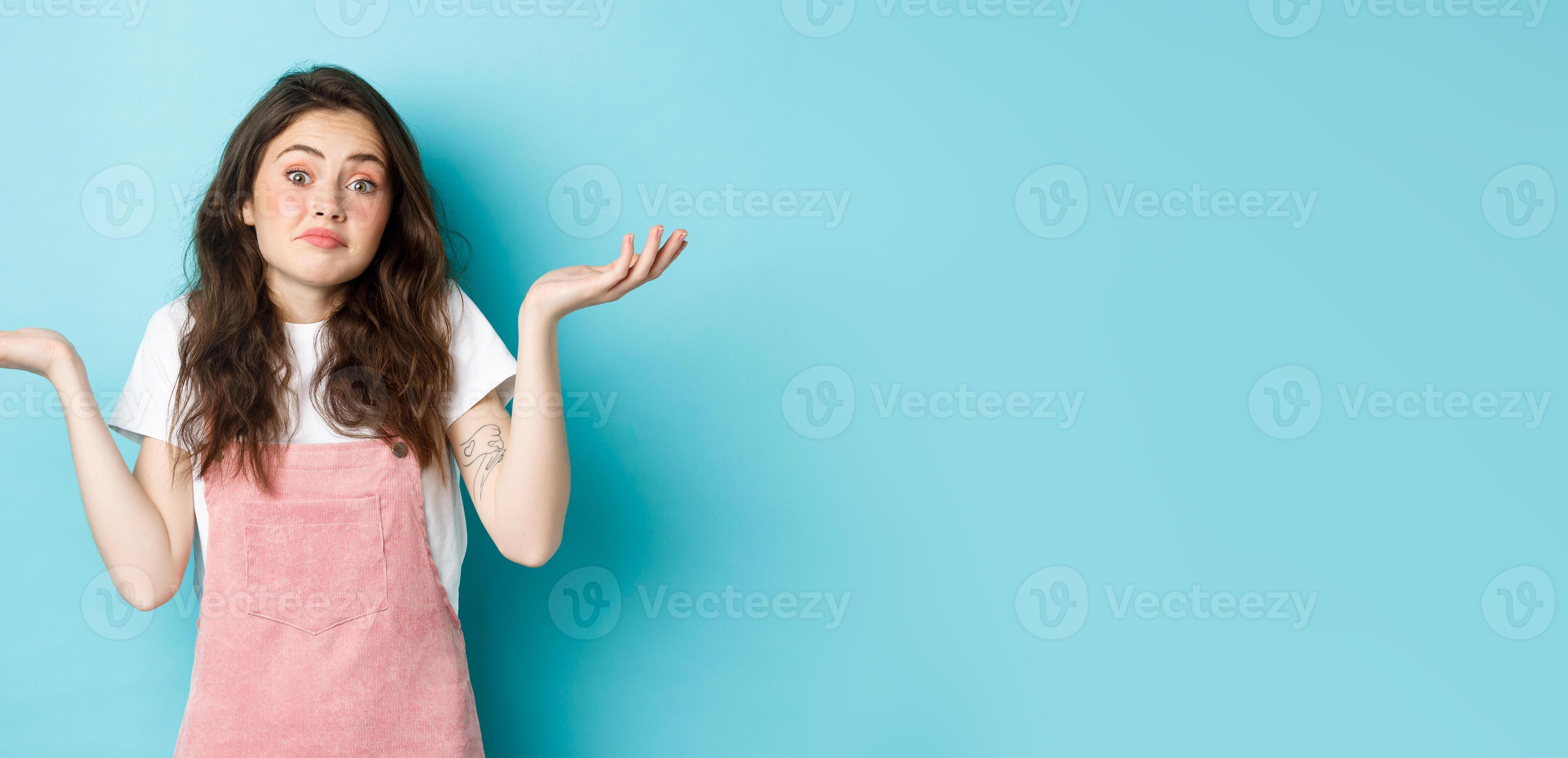 Portrait of confused cute brunette girl shrugging shoulders, know ...