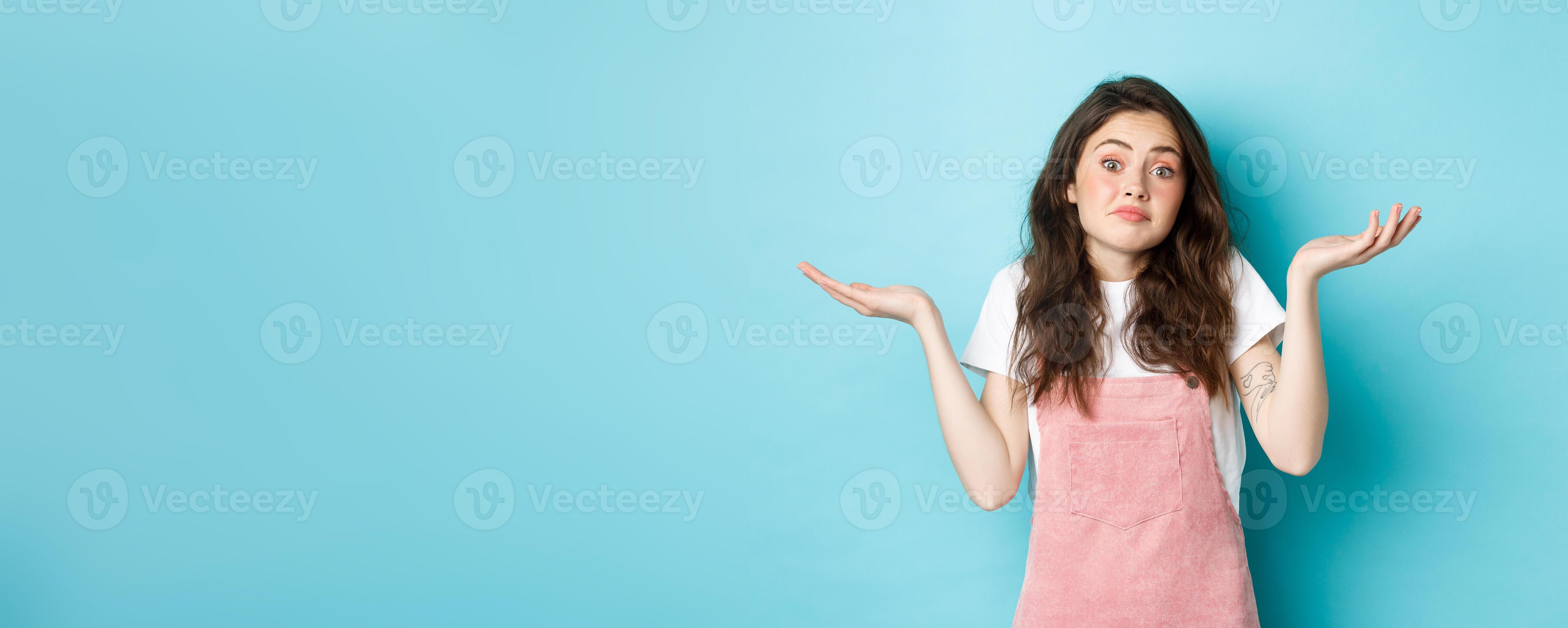 Portrait of confused cute brunette girl shrugging shoulders, know ...