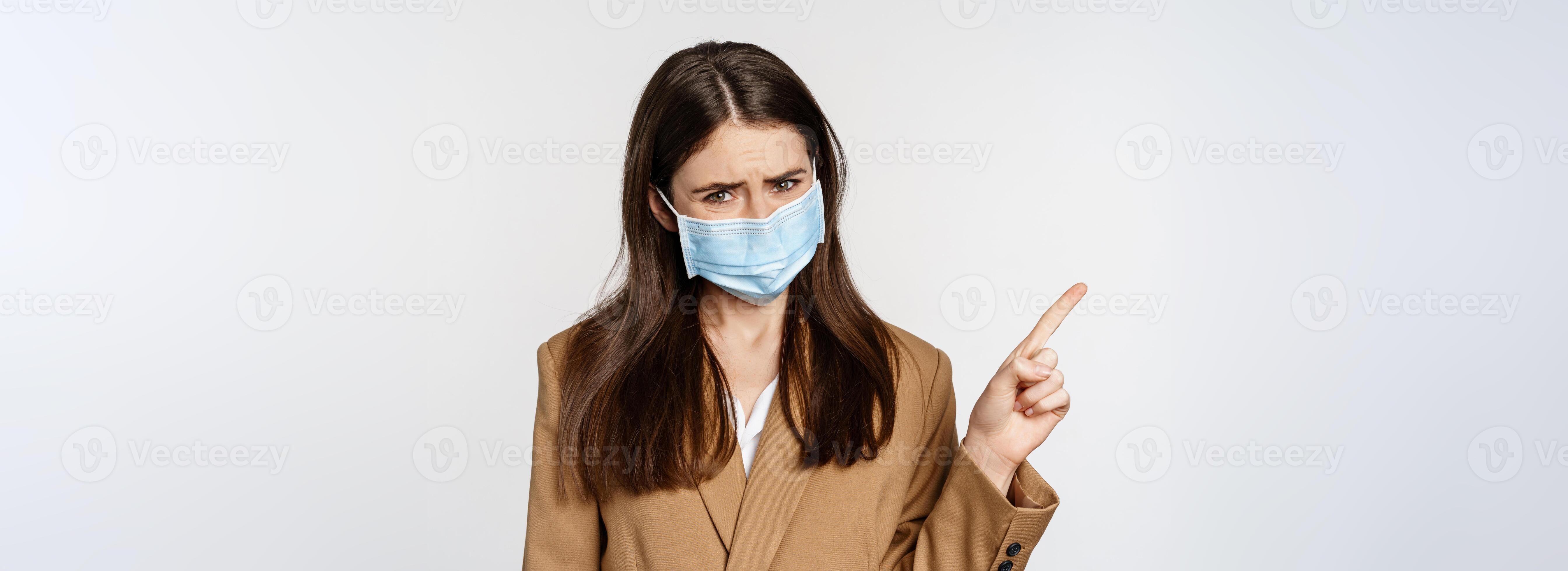 Coronavirus and people concept. Sad and concerned woman in office clothing and medical face mask ...