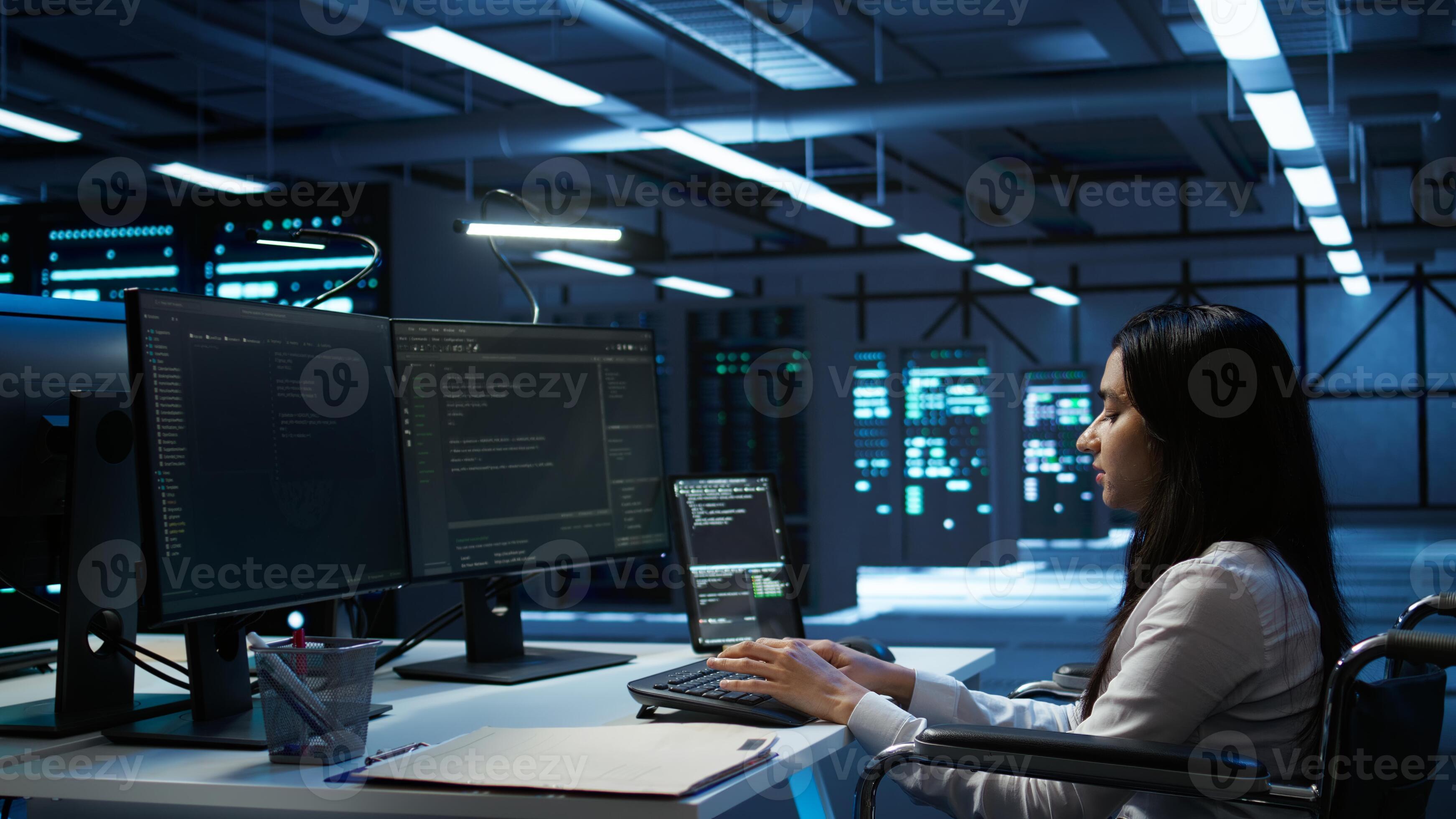 System administrator in wheelchair overseeing data center using computer, ensuring system can ...