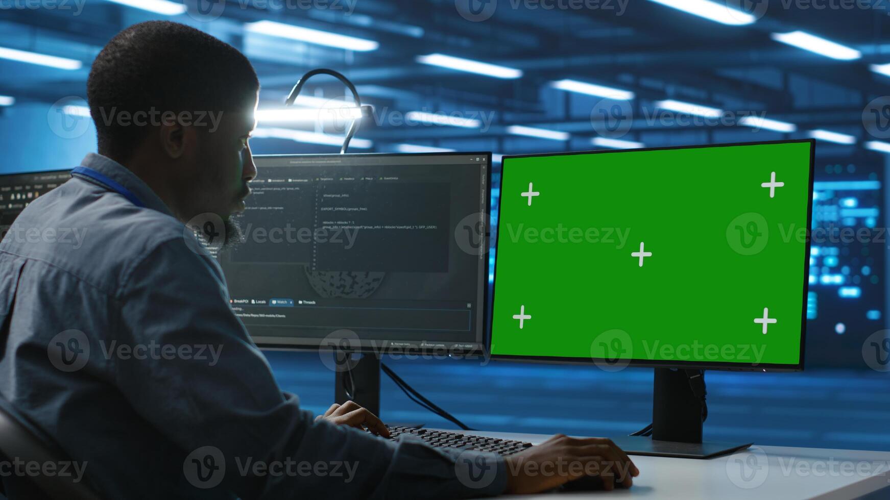 IT specialist in server farm using green screen PC ensuring valuable data remains shielded from ...