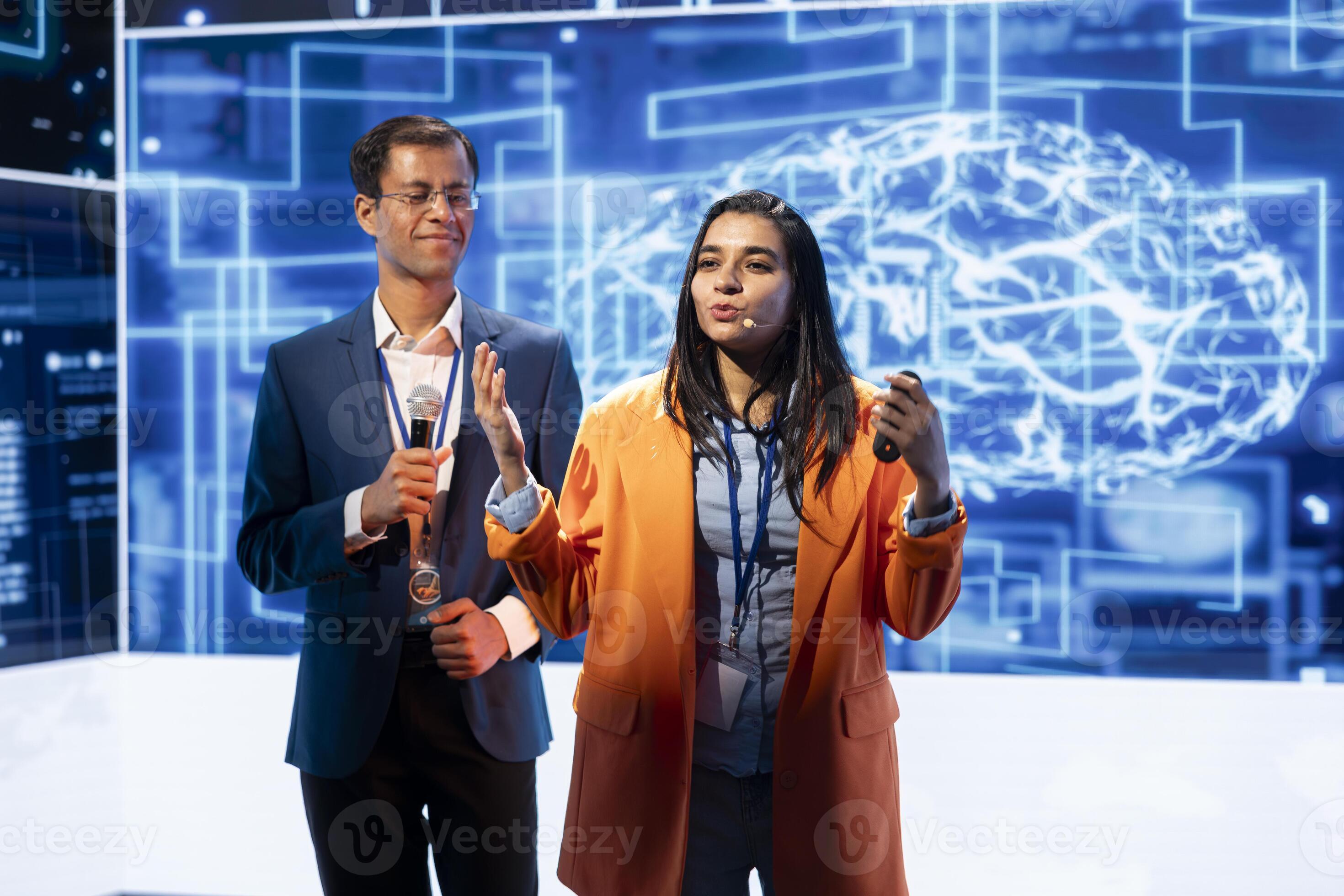 Presenter and guest chatting during AI summit discussion panel bringing ...