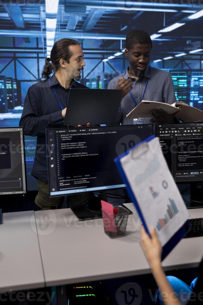 Man Inspecting Server Hub Infrastructure Reading Paperwork From Folder
