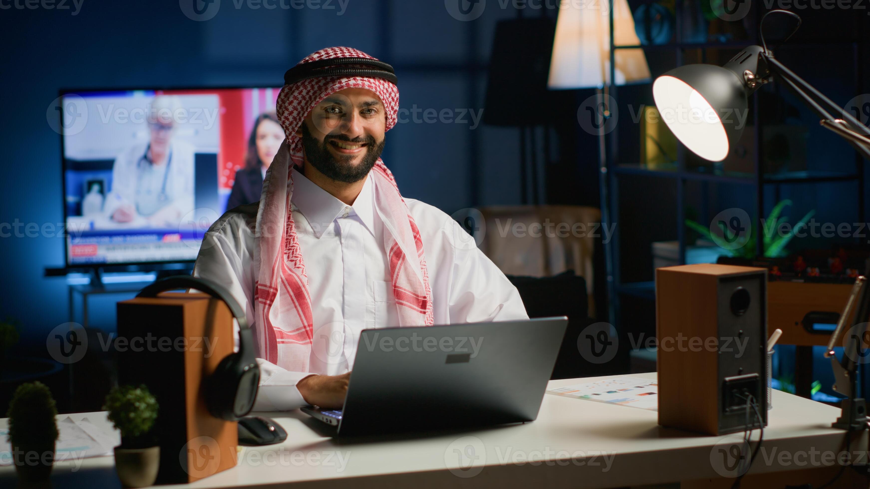 Portrait of happy Arab businessman working at home desk, typing on his ...