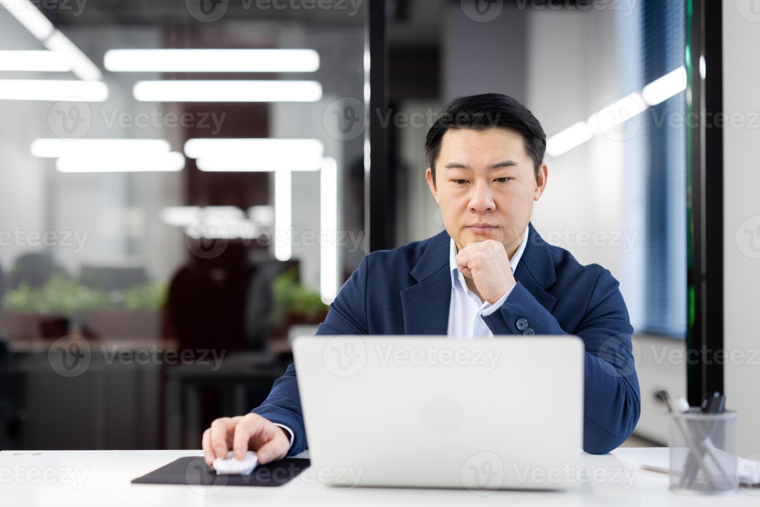 A dedicated professional man engages with a laptop at a desk in a well-lit contemporary office ...