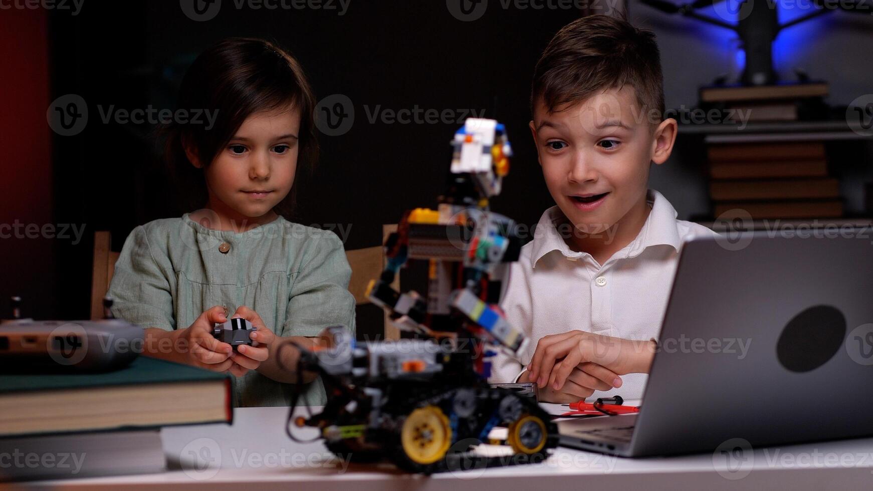 Two kids programming robot from laptop using wireless controller ...
