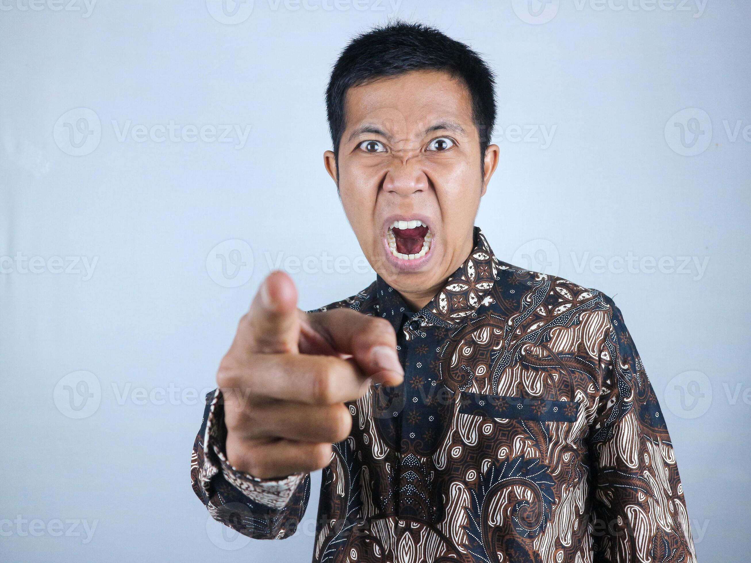 angry face expression of asian man wearing batik clothes while pointing ...