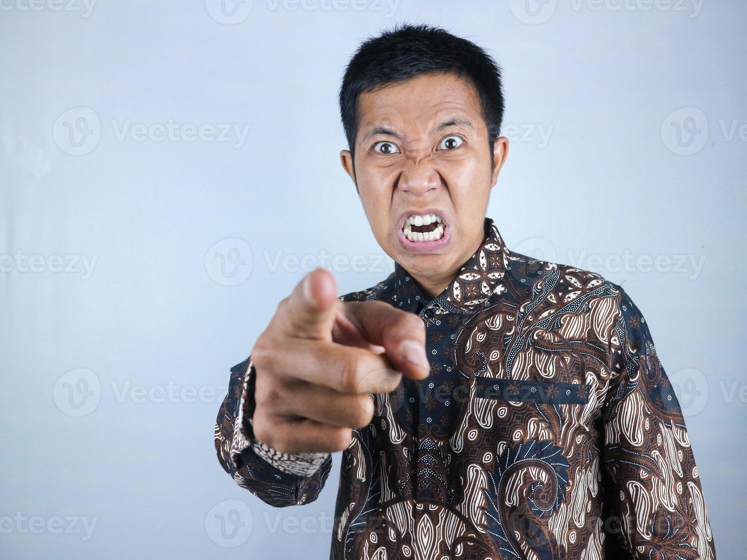 angry face expression of asian man wearing batik clothes while pointing ...