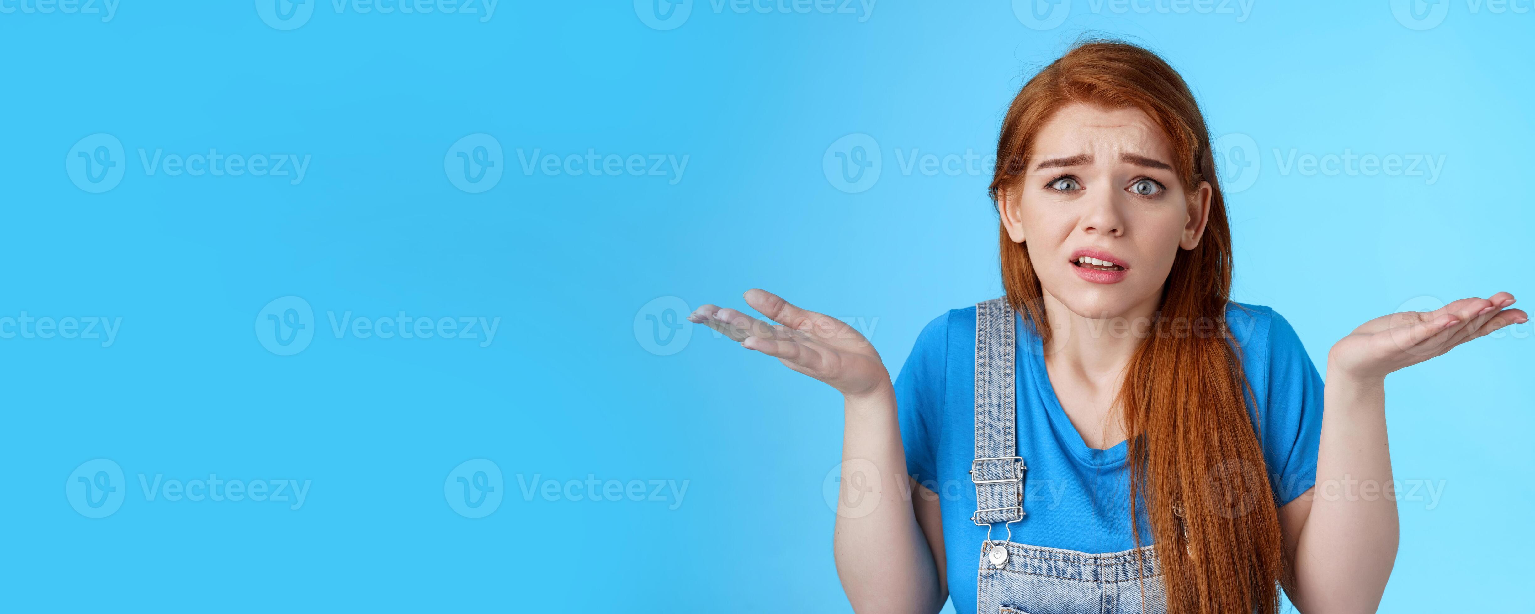 Perplexed uneasy stupified worried redhead woman shrugging, have no ...