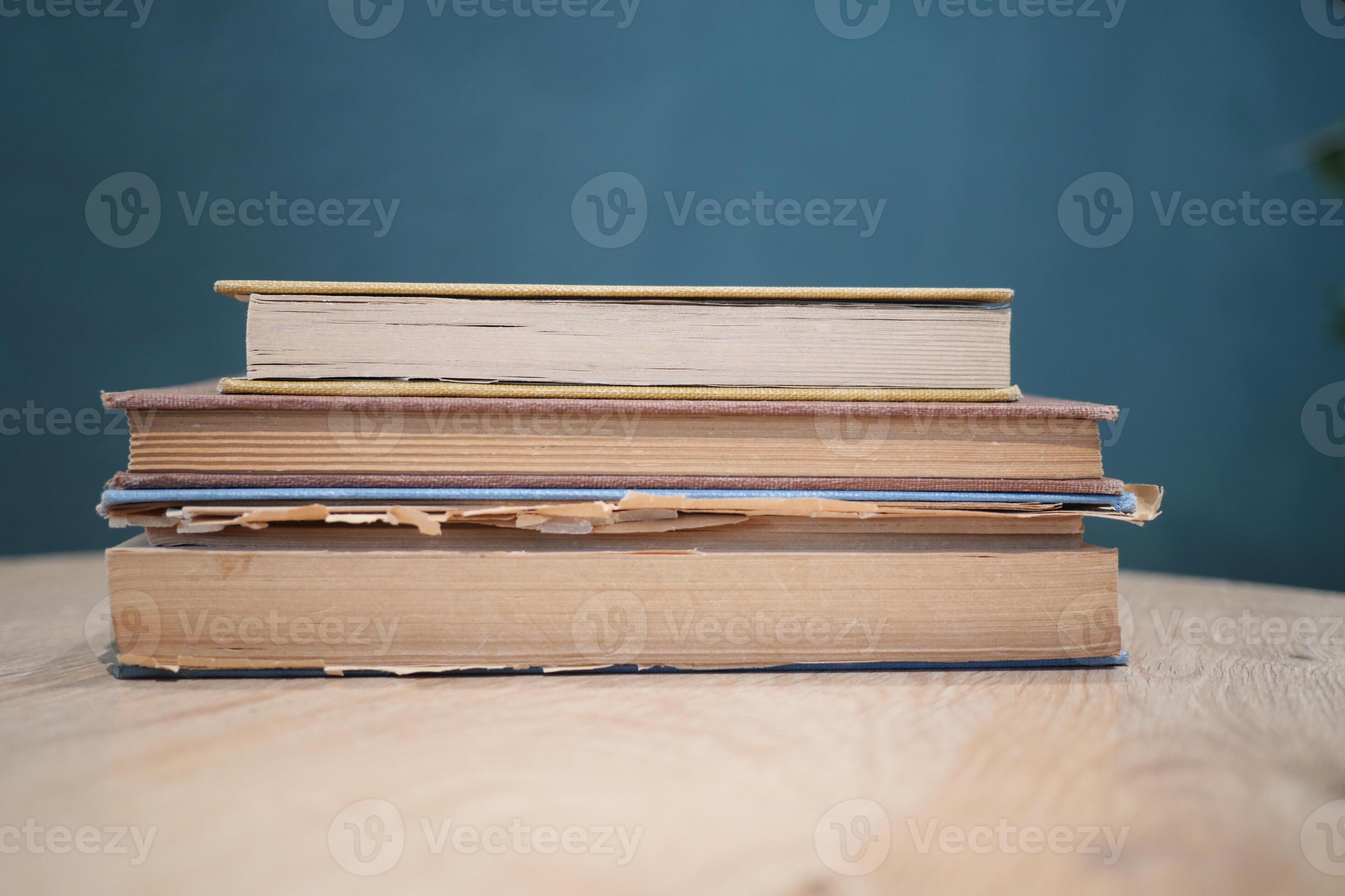 An open book with its pages gently turning rests on a wooden table in ...