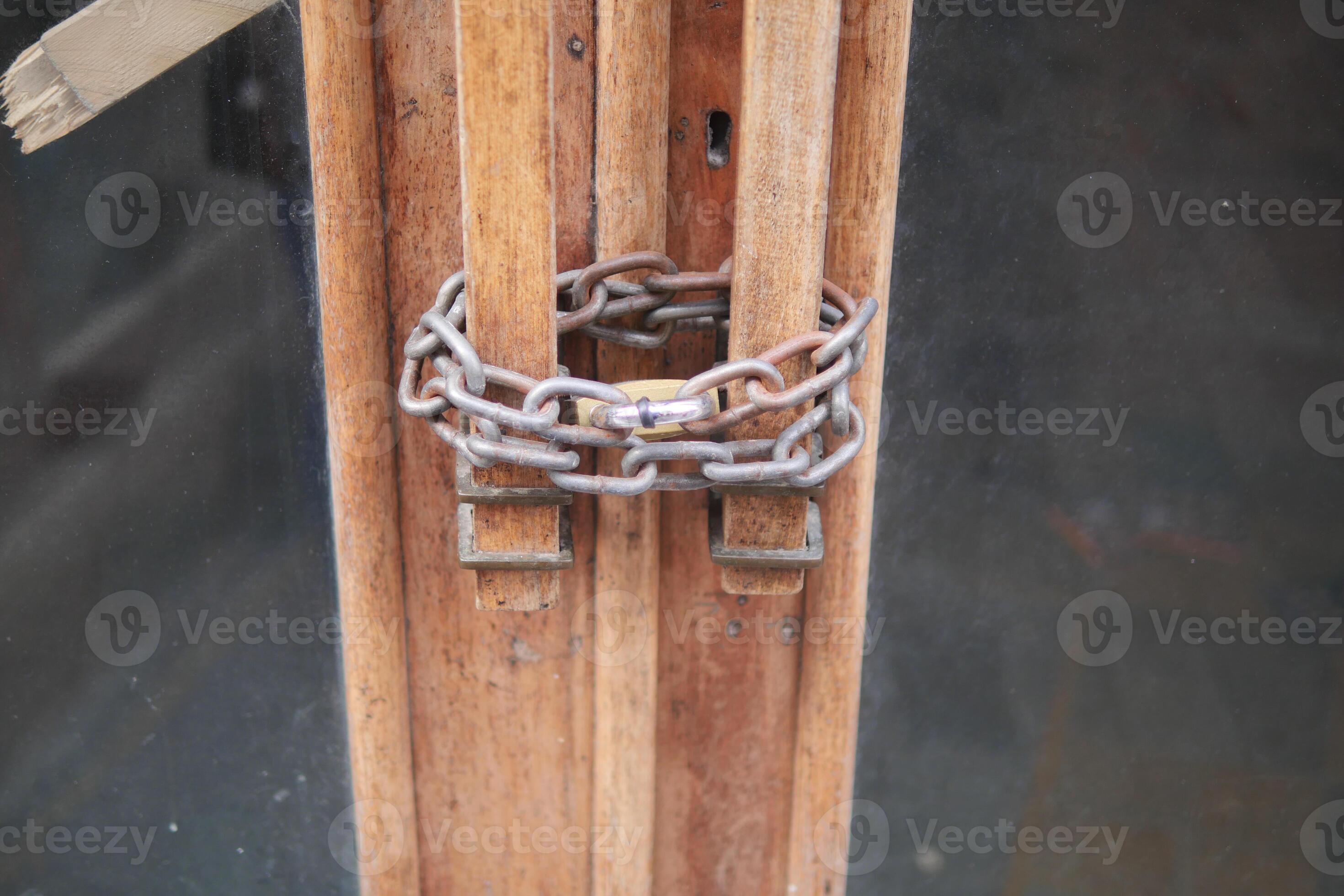 A set of locked wooden doors secured with a robust chain and a sturdy padlock for safety ...