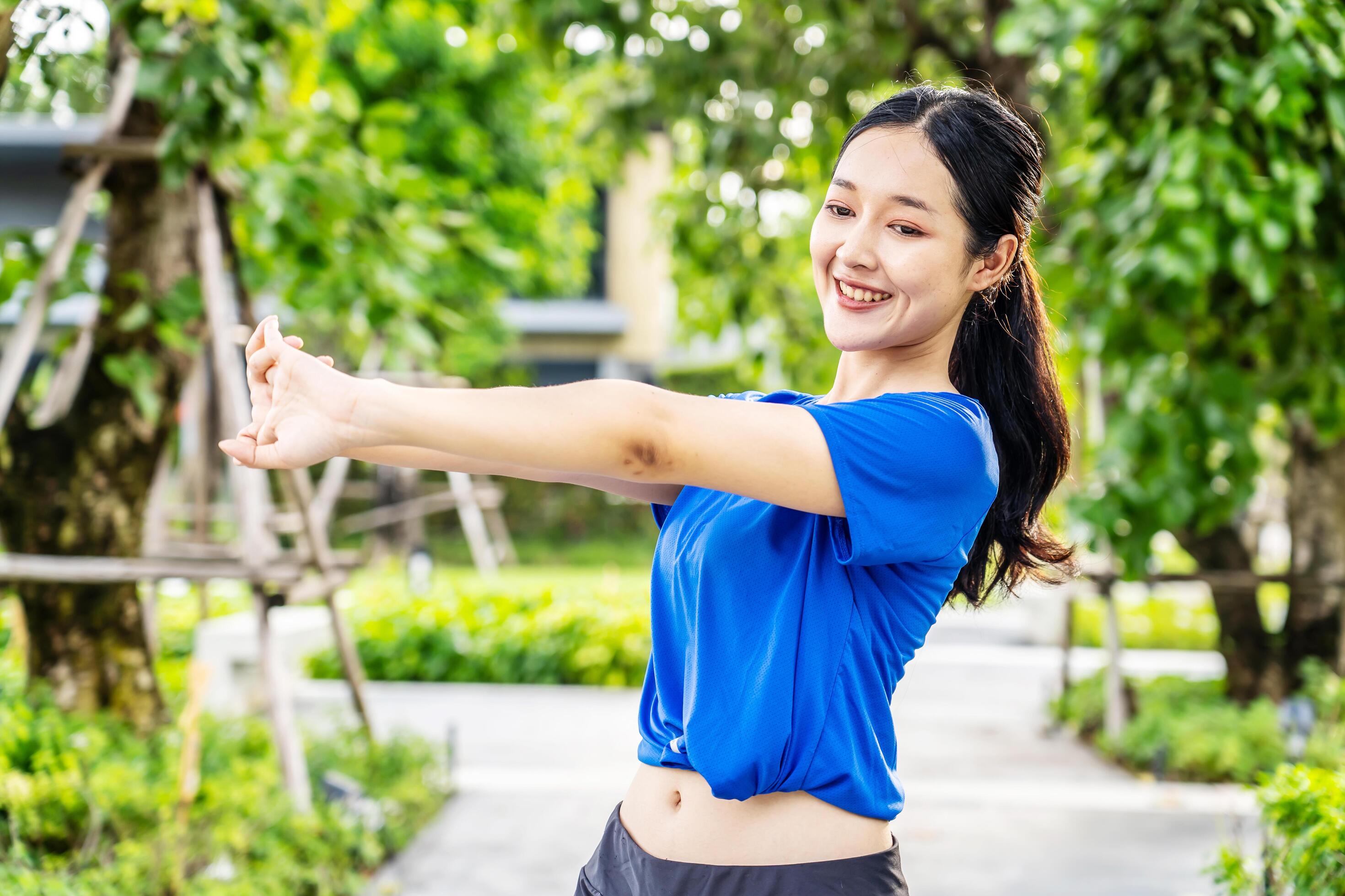 Strong athletic asian woman stretching warming up before running. Fit sport girl stretching her ...