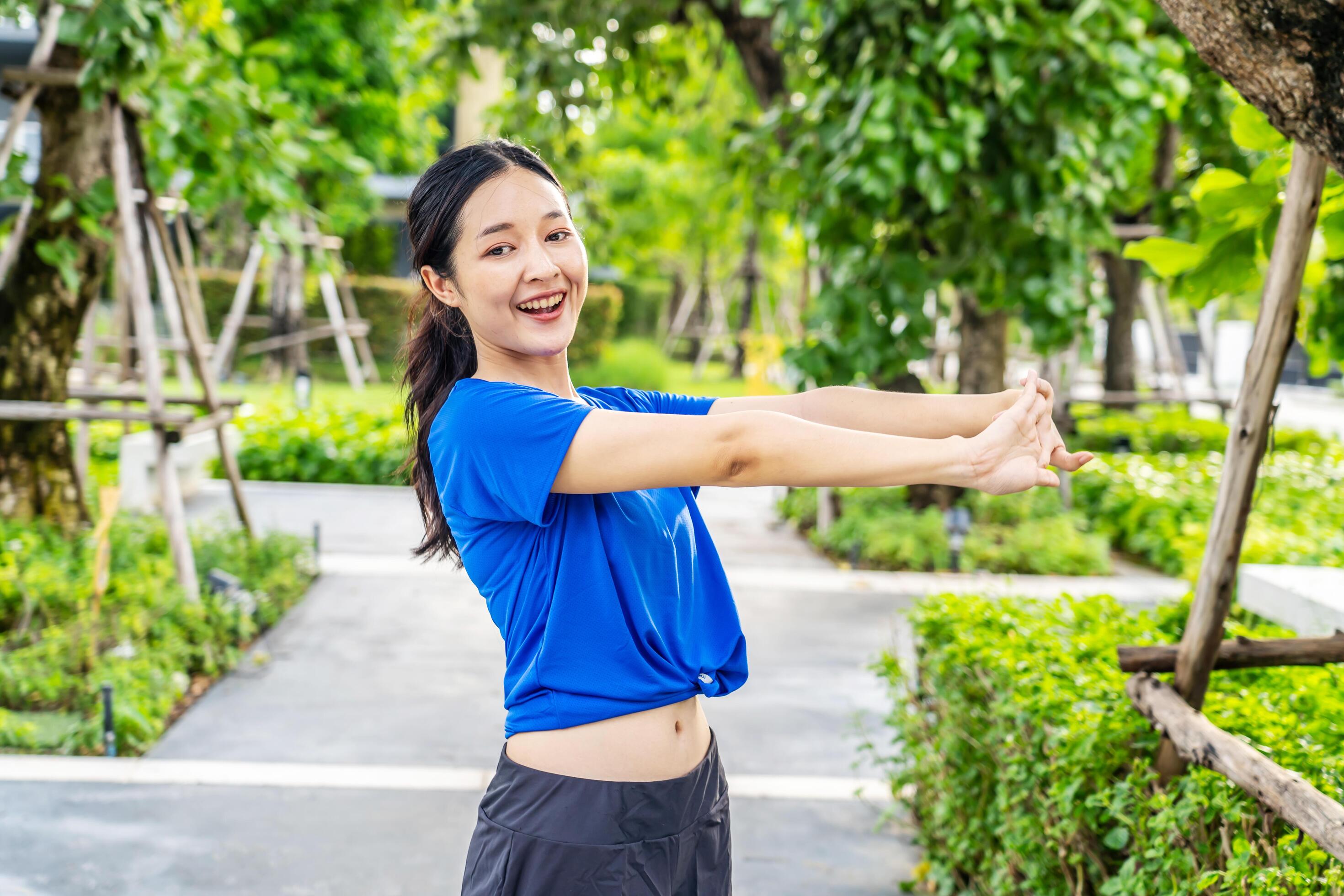 Strong athletic asian woman stretching warming up before running. Fit sport girl stretching her ...