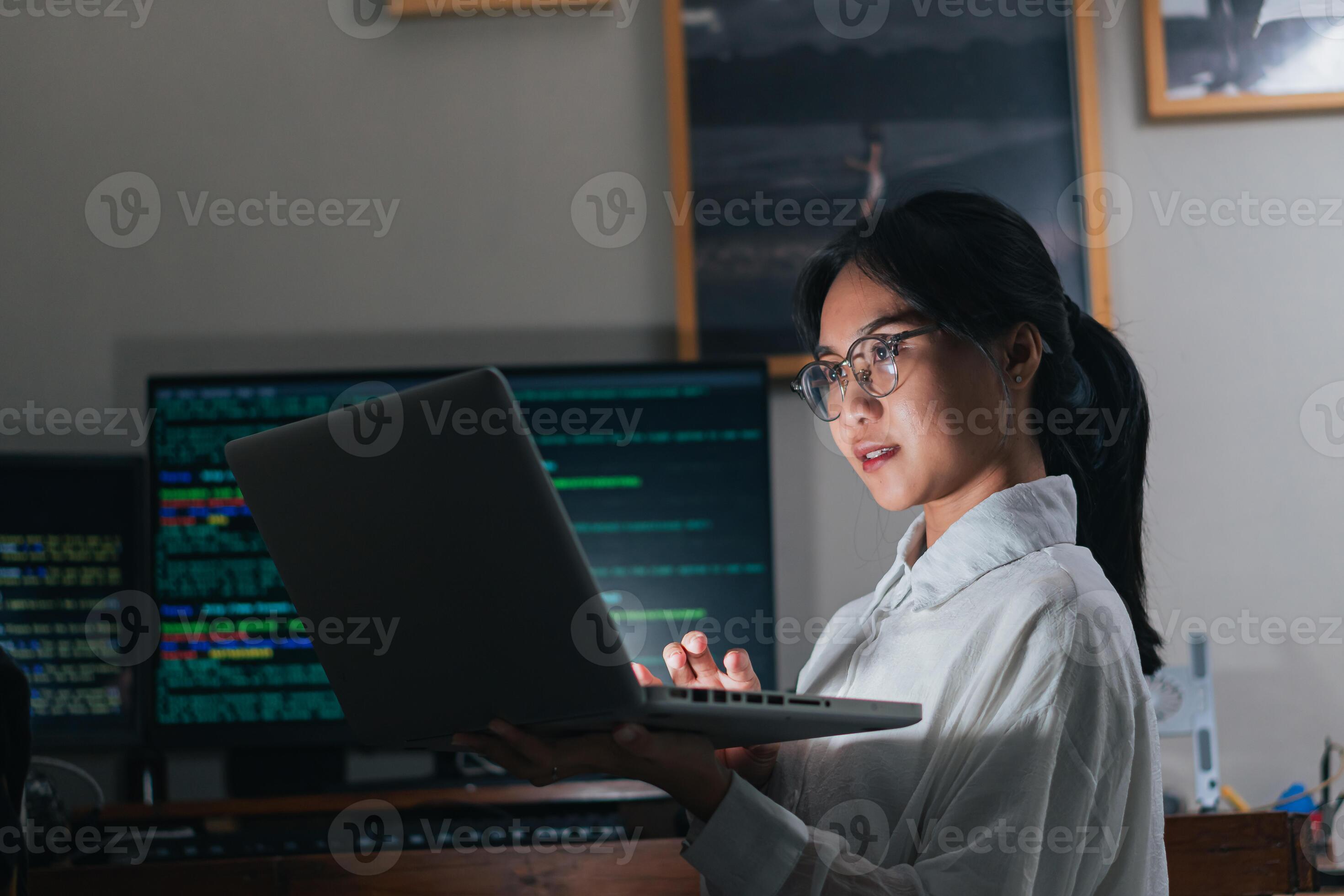 Young Woman Coding on Laptop in Dimly Lit Room 50207835 Stock Photo at Vecteezy