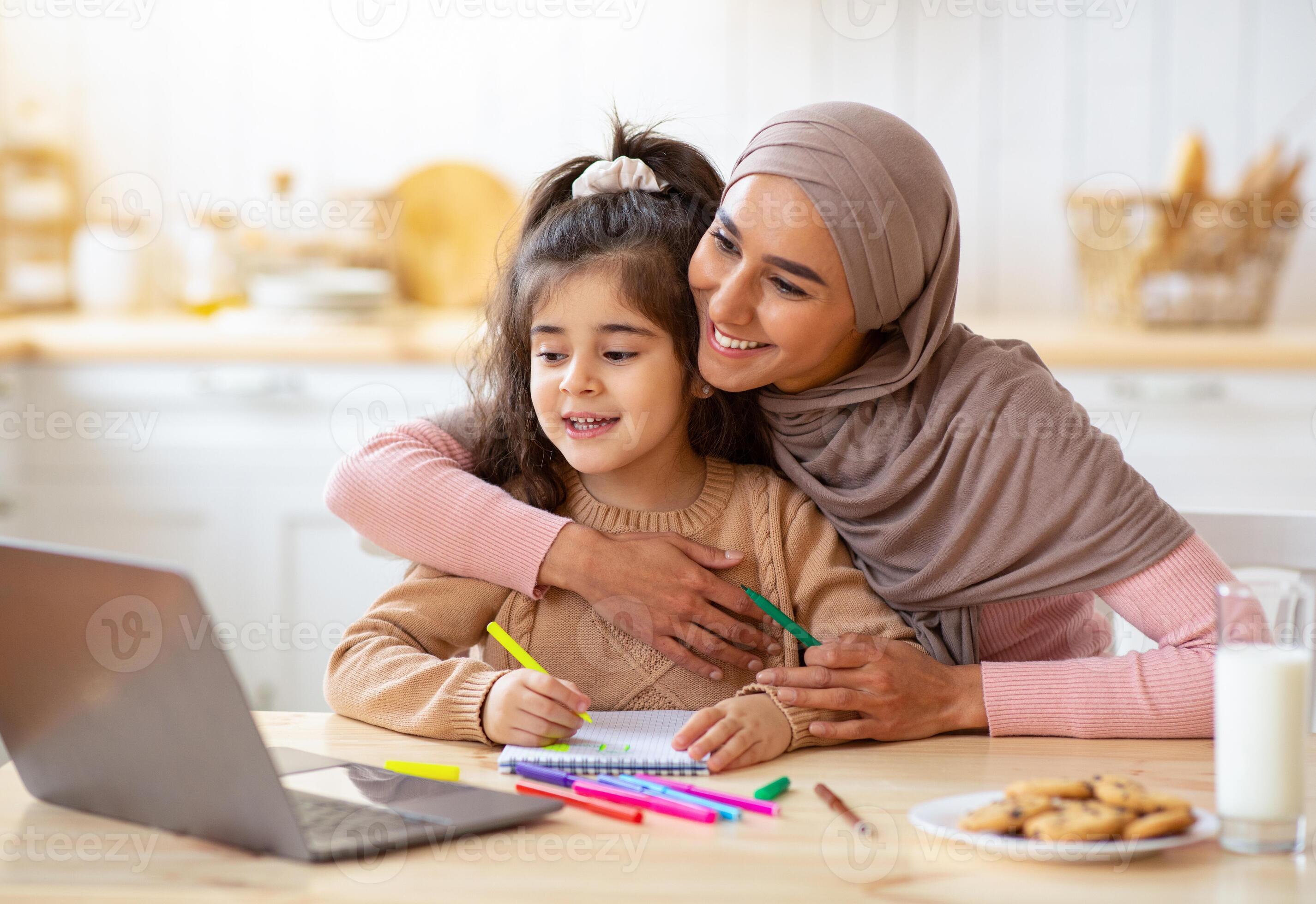 Happy Muslim Mom In Hijab And Her Little Daughter Using Laptop In ...
