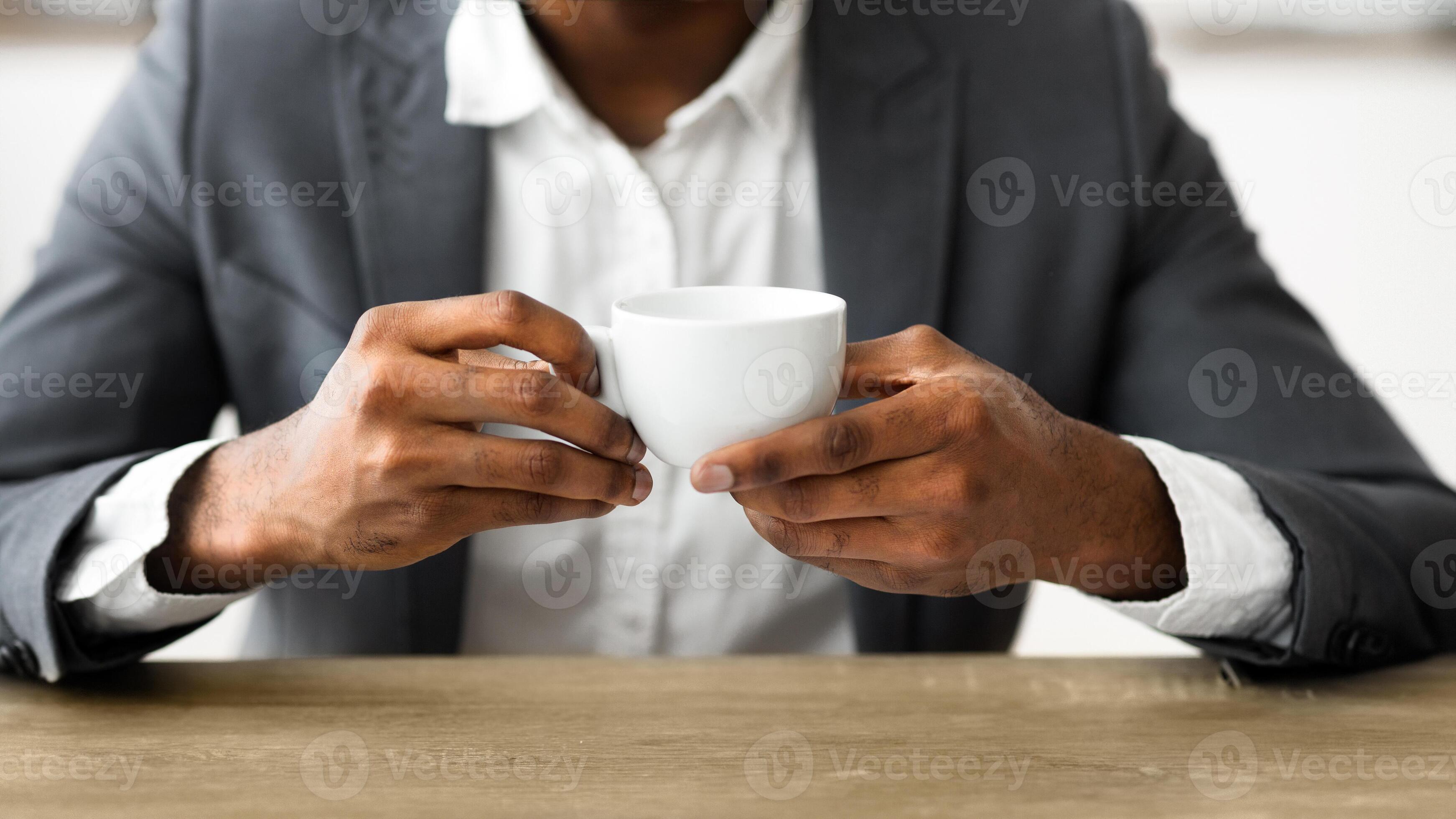 African american businessman drinking coffee at workplace, having a break in modern office ...