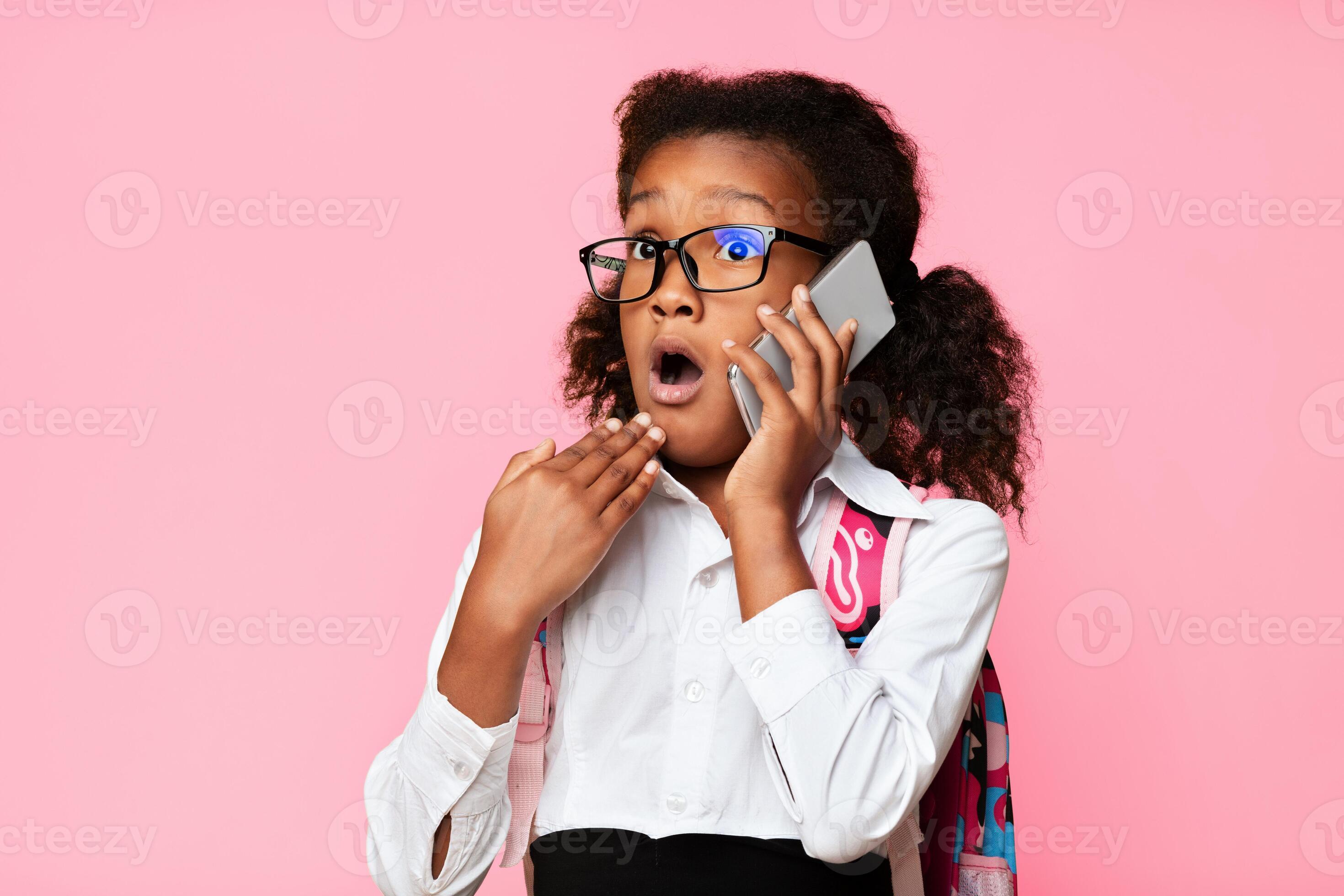 OMG, School News. Surprised Afro Schoolgirl Talking On Phone Over Yellow Studio Background. Free ...