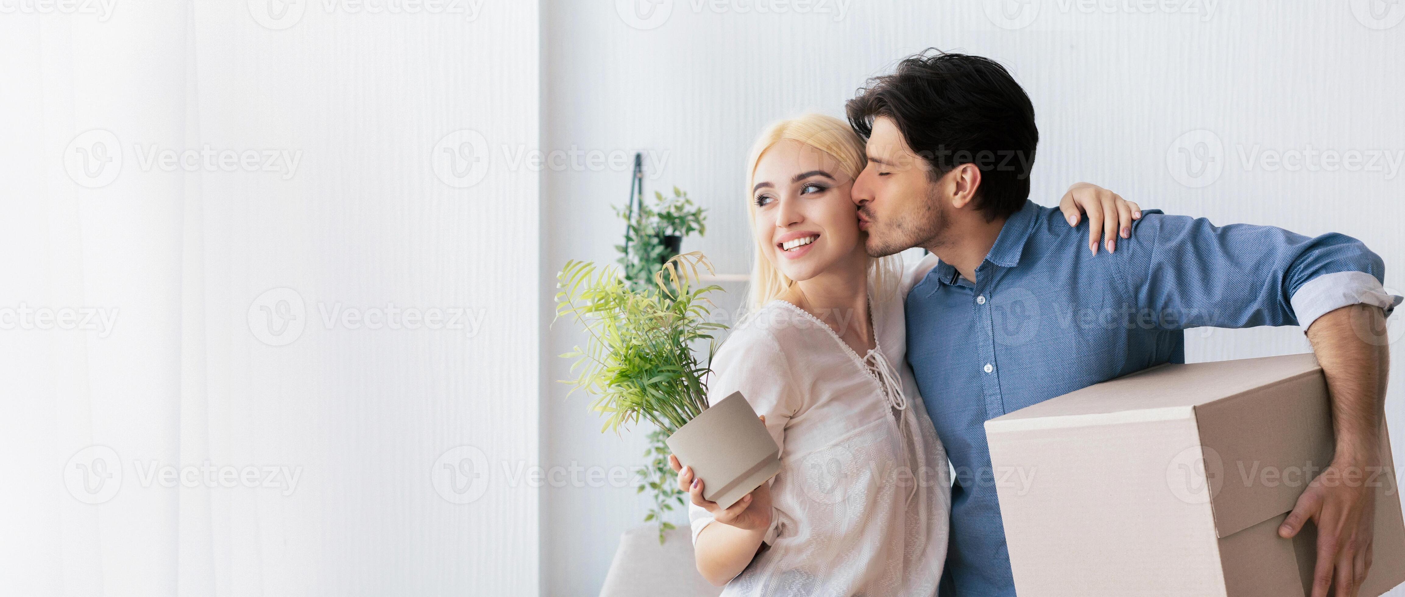 Moving House Concept. Man Kissing Woman Holding Box Unpacking In New House. Free Space For Text ...