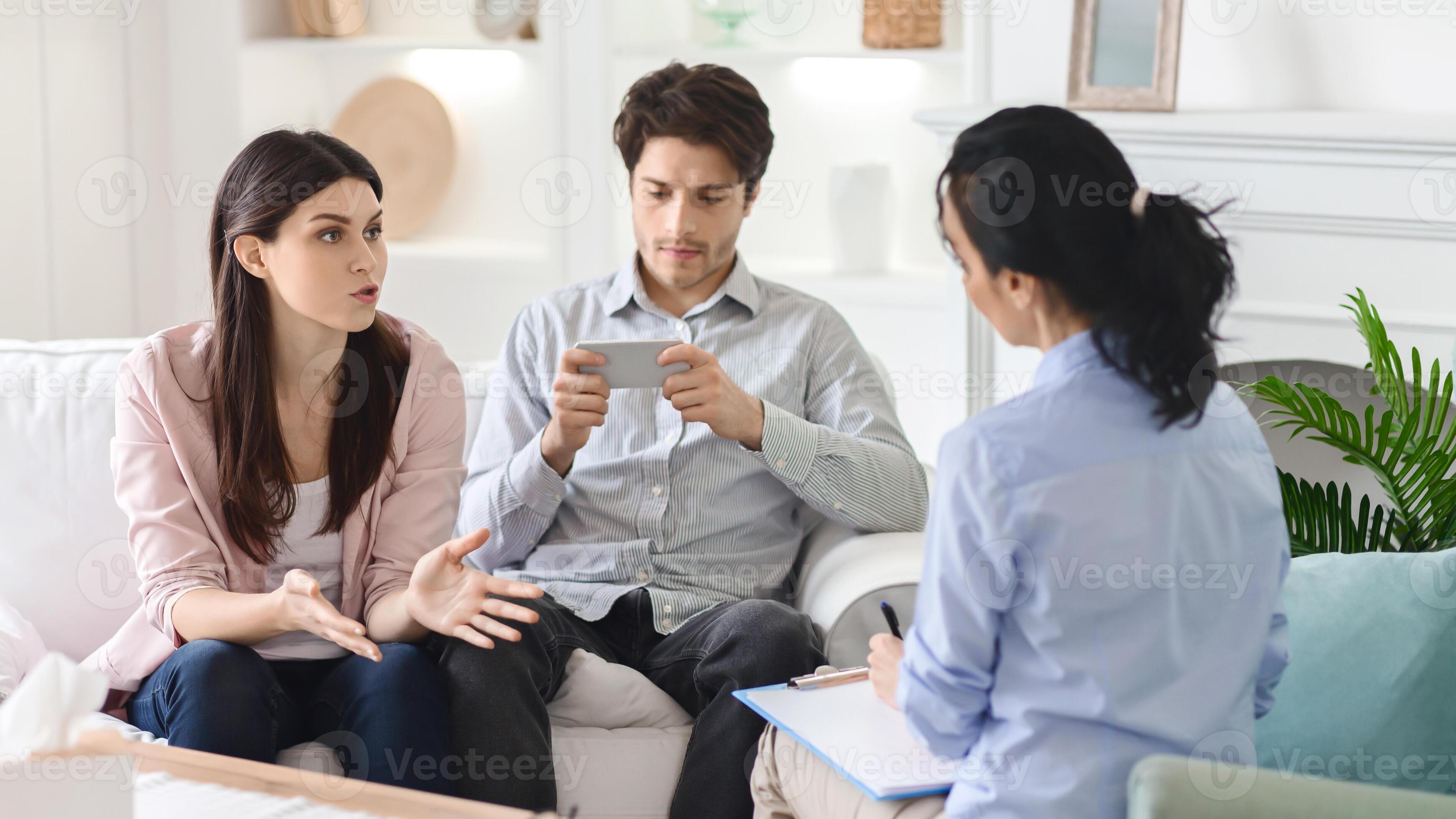 Indifferent young man husband using phone during family session with ...