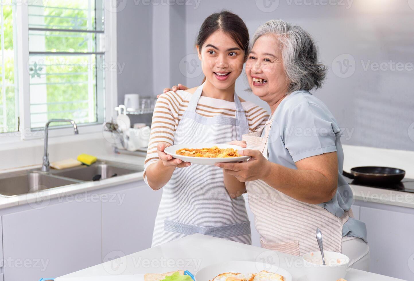 Cheerful senior asian mother and middle aged daughter cooking together at kitchen, Asian woman ...