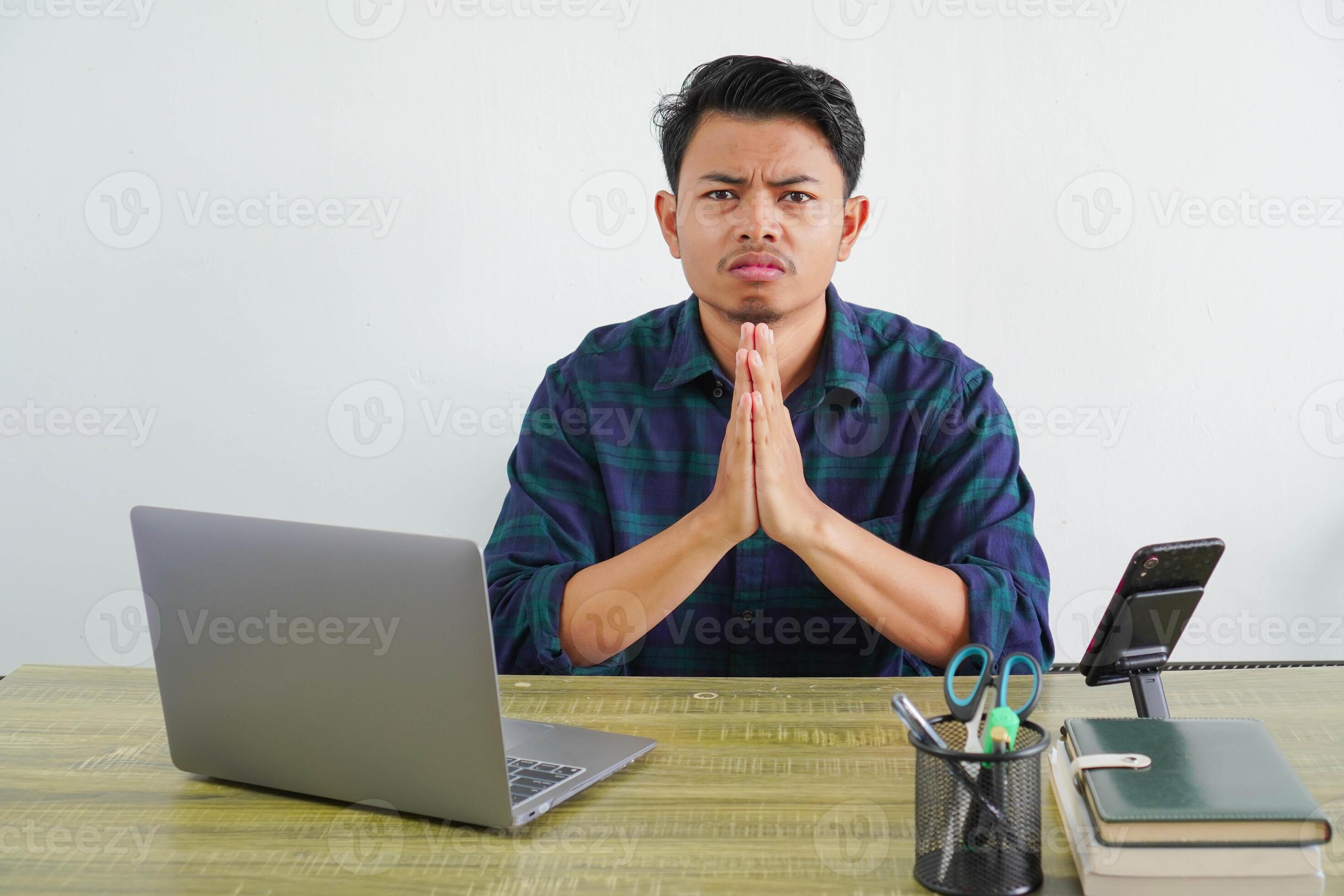 Pleading young asian man sit work at wooden desk with pc laptop ...