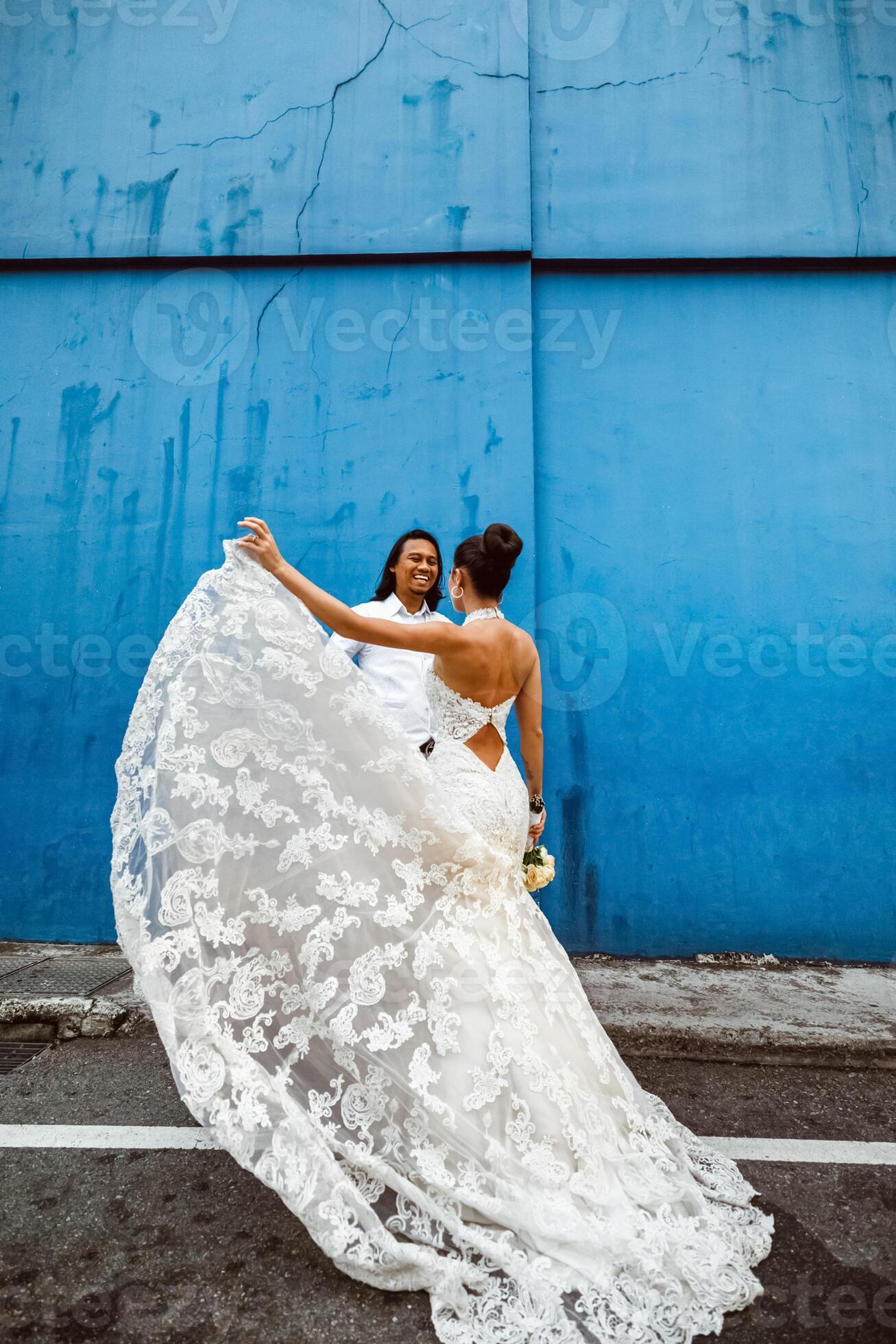 A beautiful European bride and an Asian groom are dancing a wedding dance against the backdrop ...