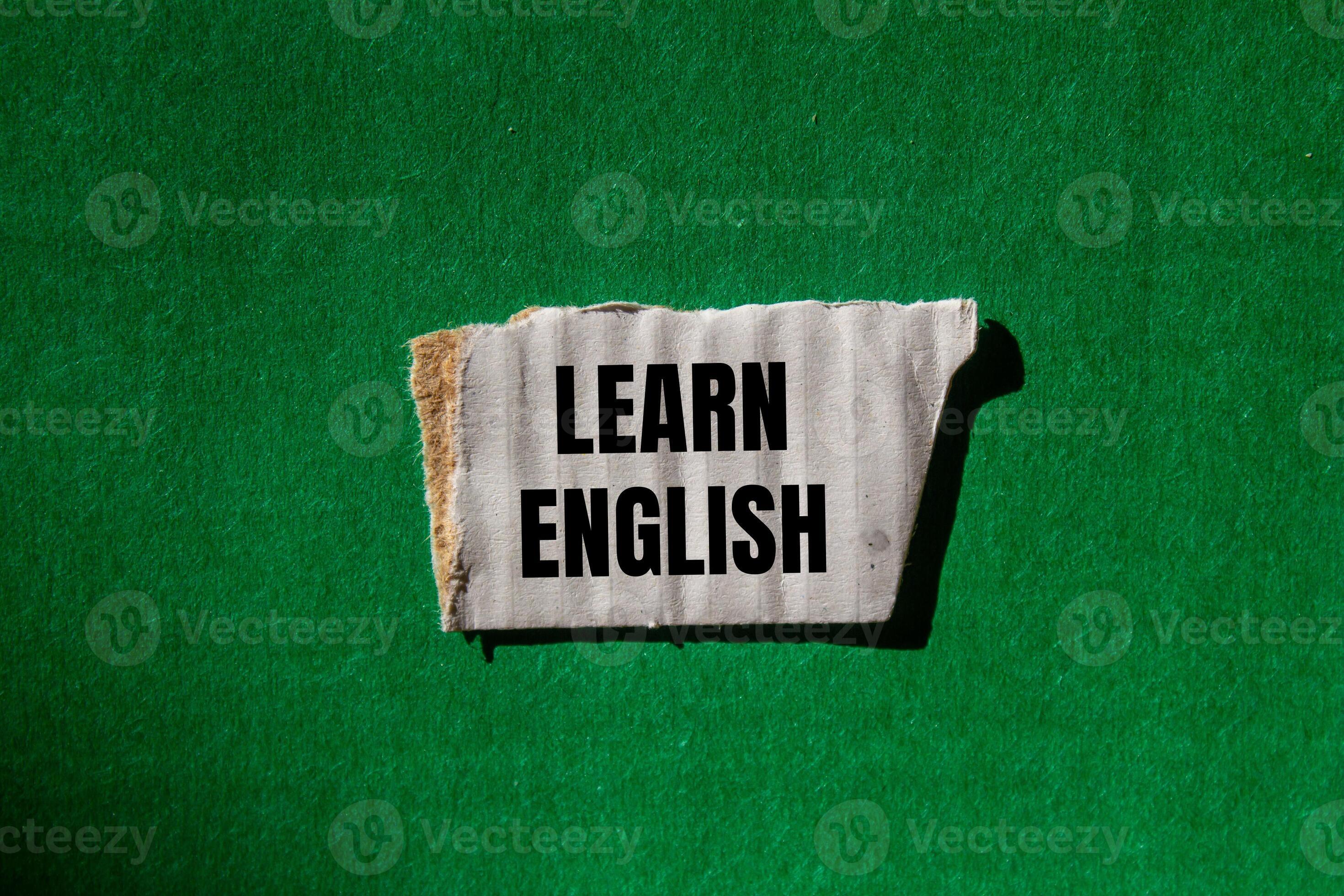 Learn english message written on ripped torn white paper piece with green background. Conceptual ...