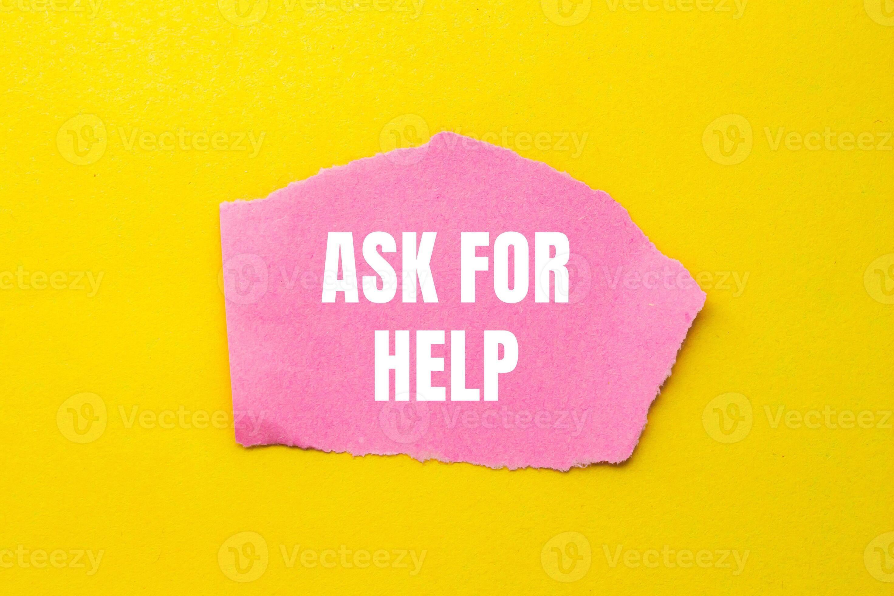Ask for help message written on ripped torn pink paper piece with yellow background. Conceptual ...