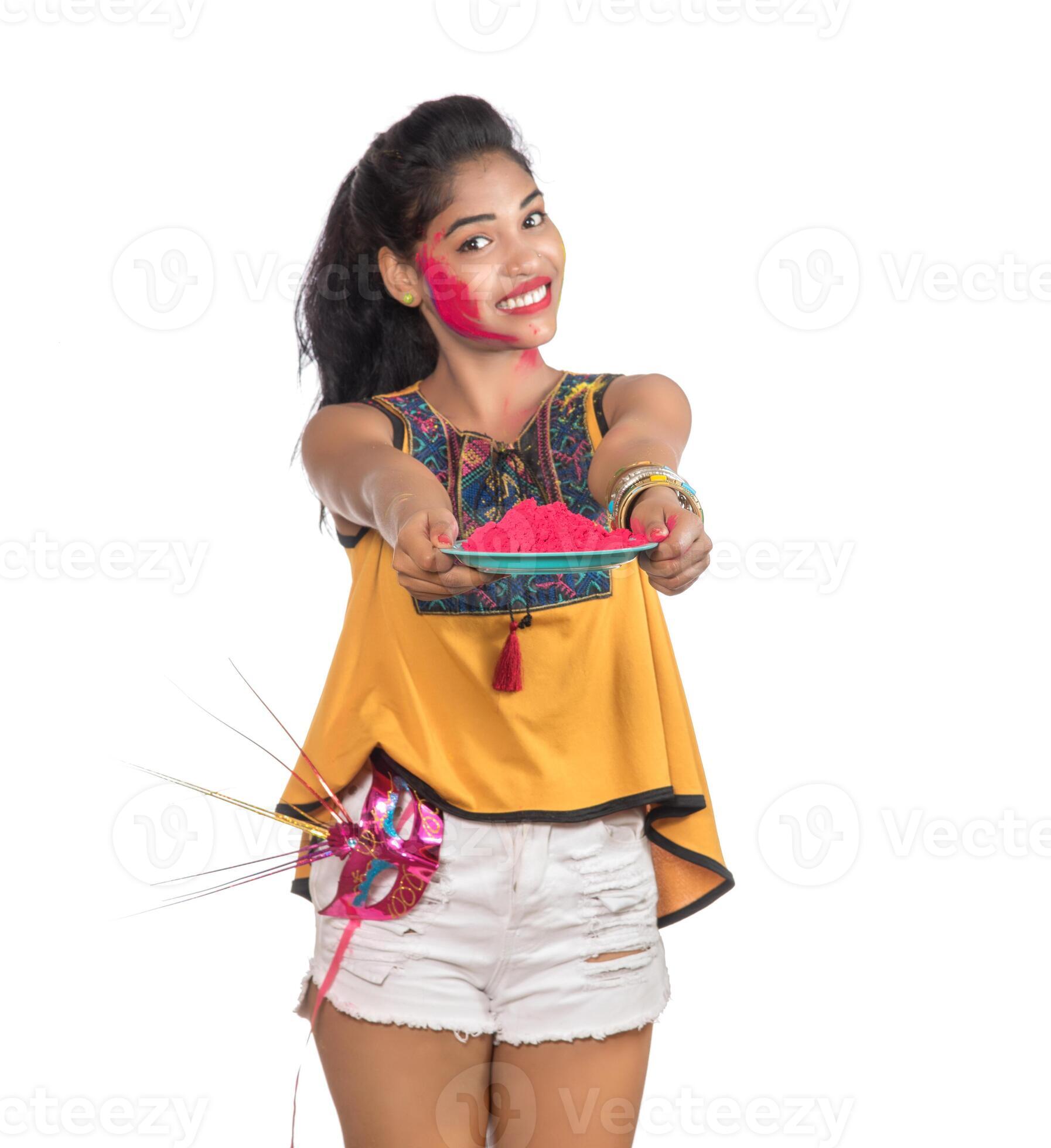 Beautiful young girl holding powdered color in plate with carnival mask on the occasion of Holi ...
