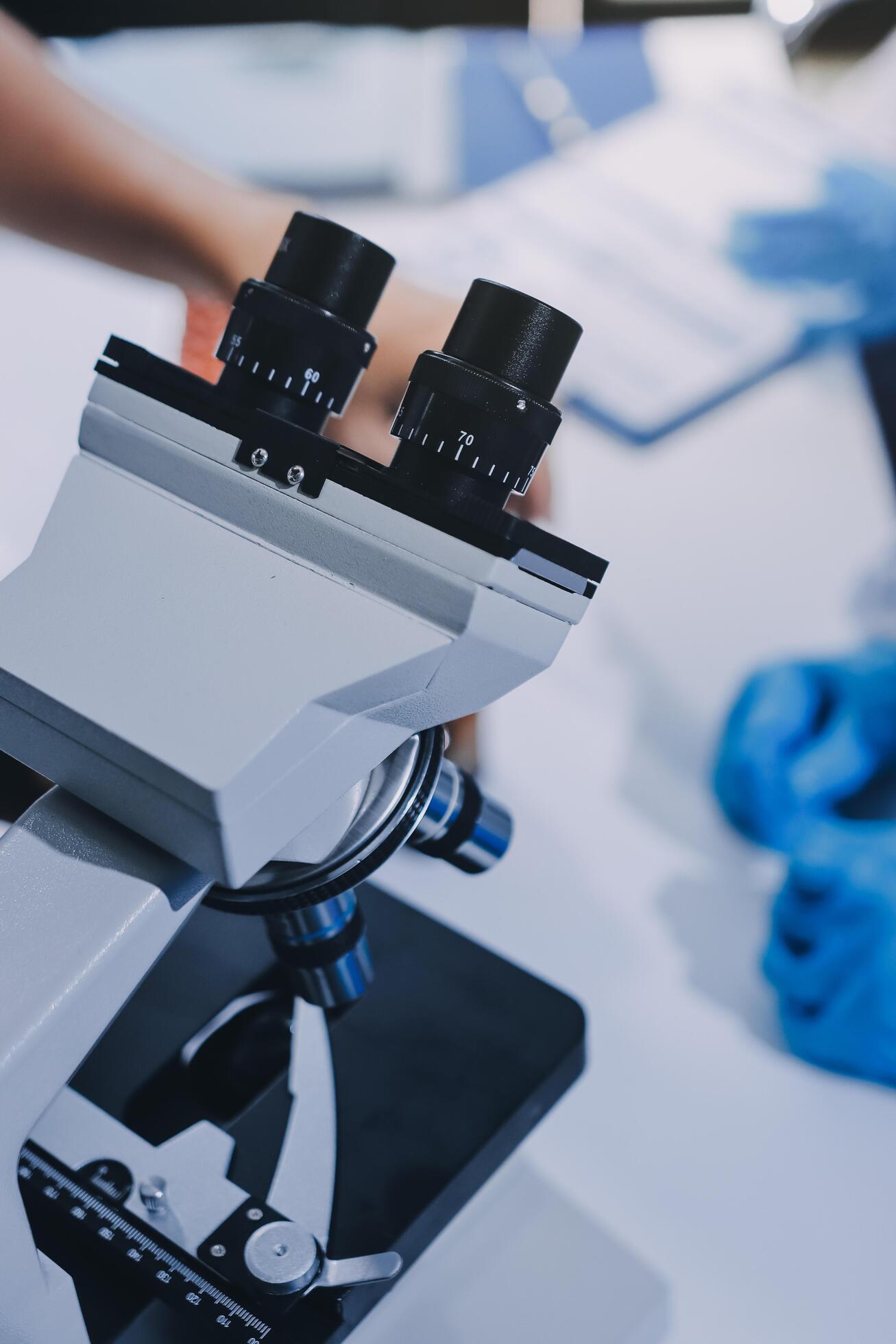 Scientist using microscope in laboratory. Close-up of a researcher's hands adjusting a modern ...