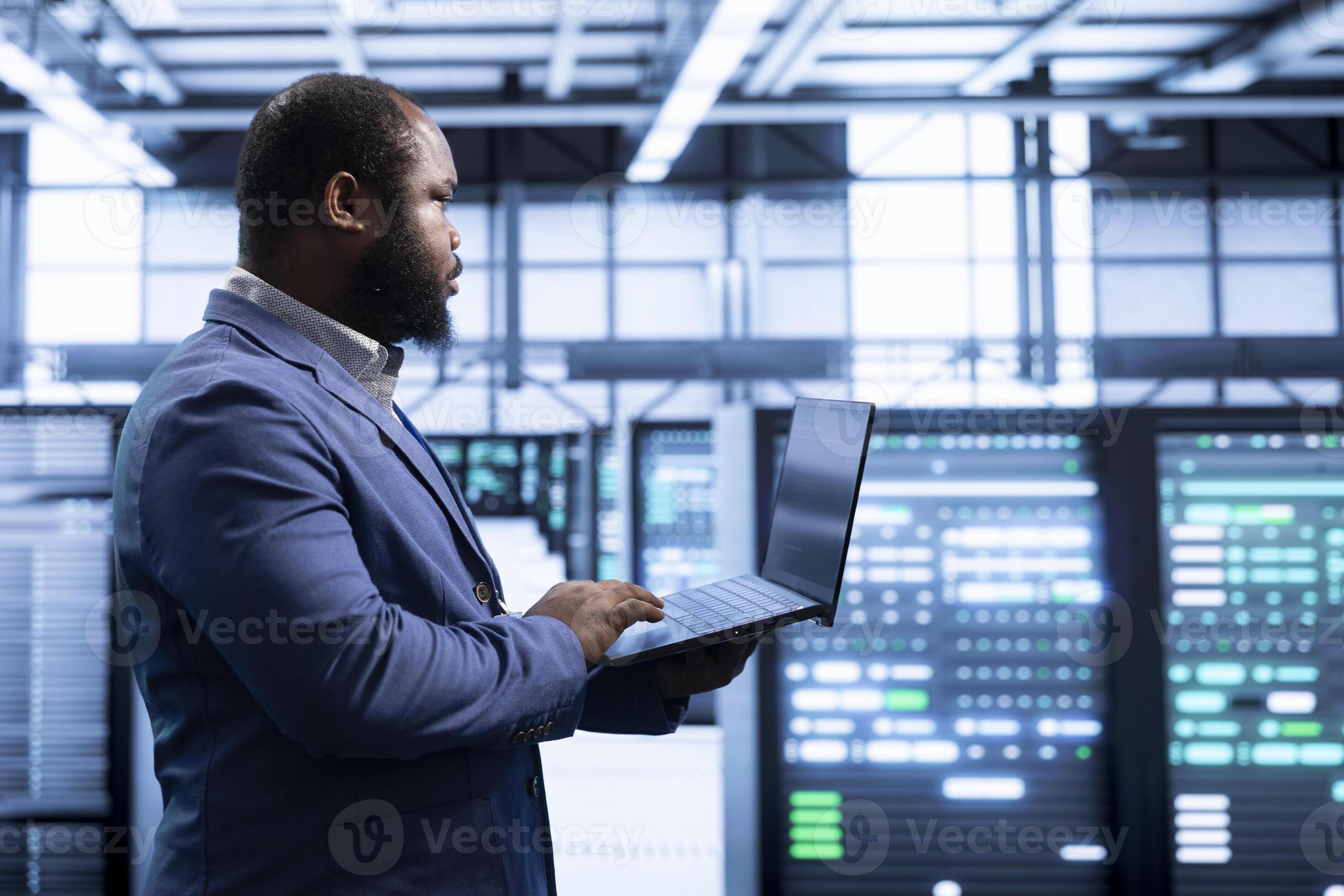 Technician in server room establishment installing newly ordered storage units using notebook ...